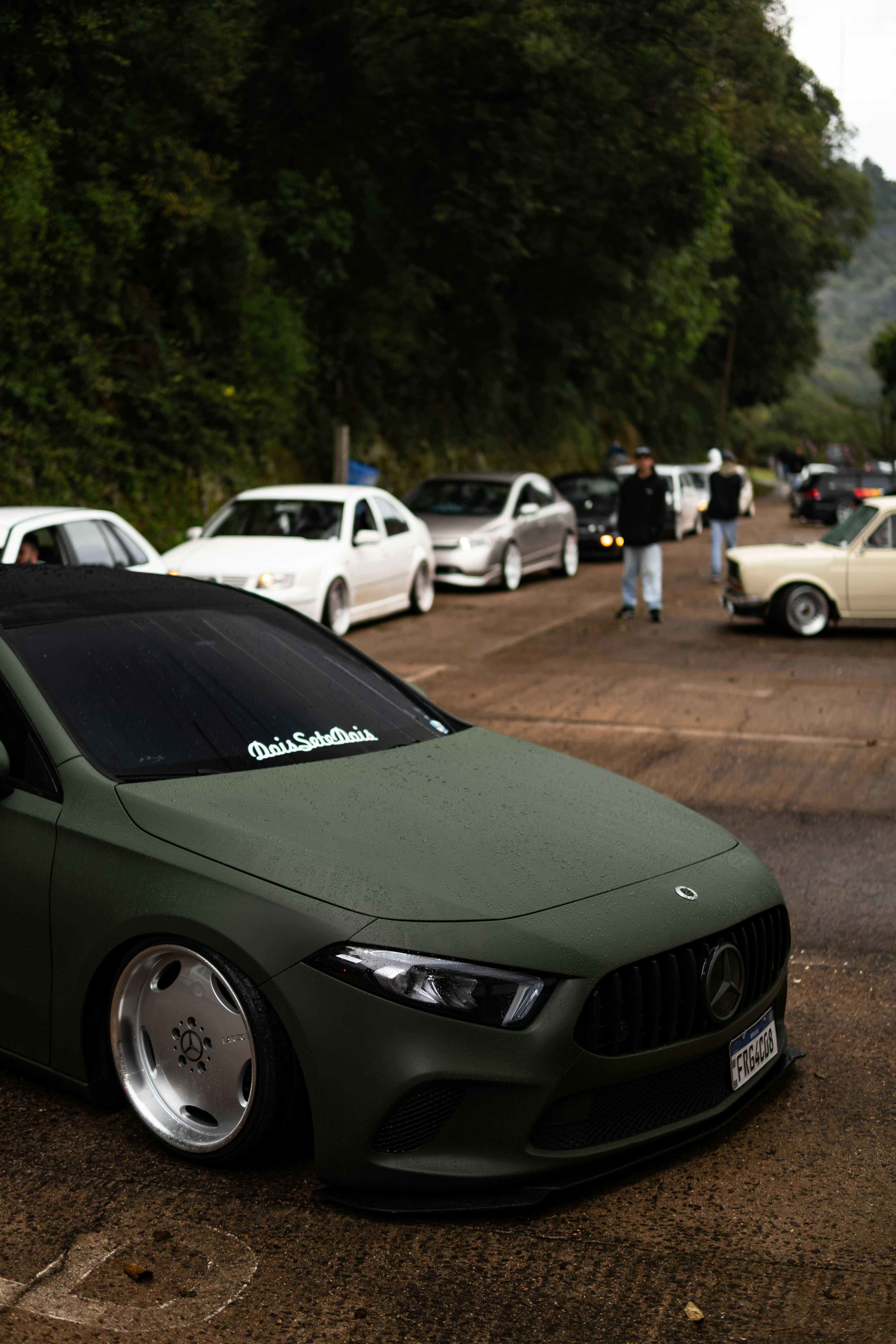 Matte-green Mercedes-Benz anchors a muddy car meet with oversized wheels