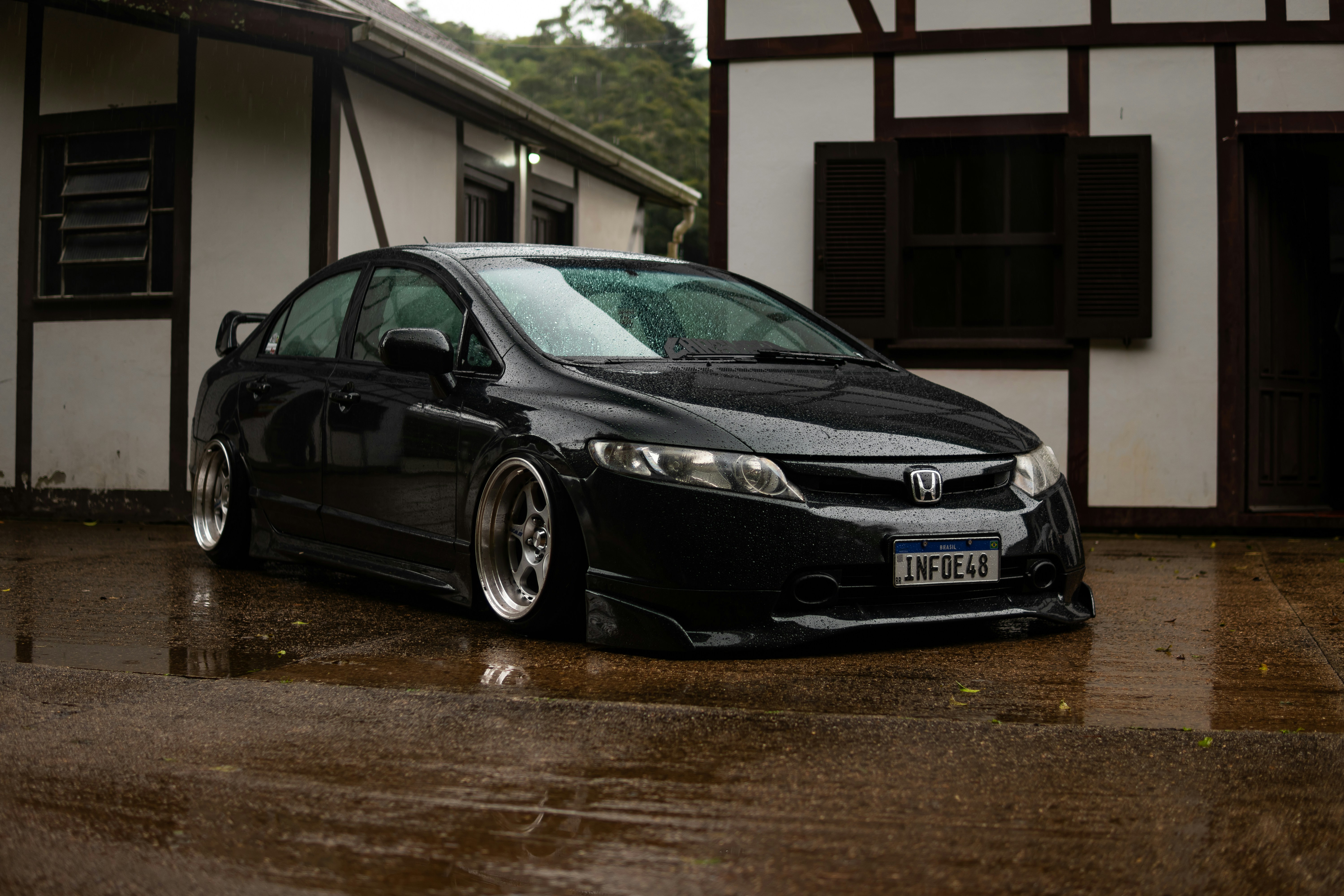 Rain-Kissed Black Honda in Front of Timber-Framed Architecture