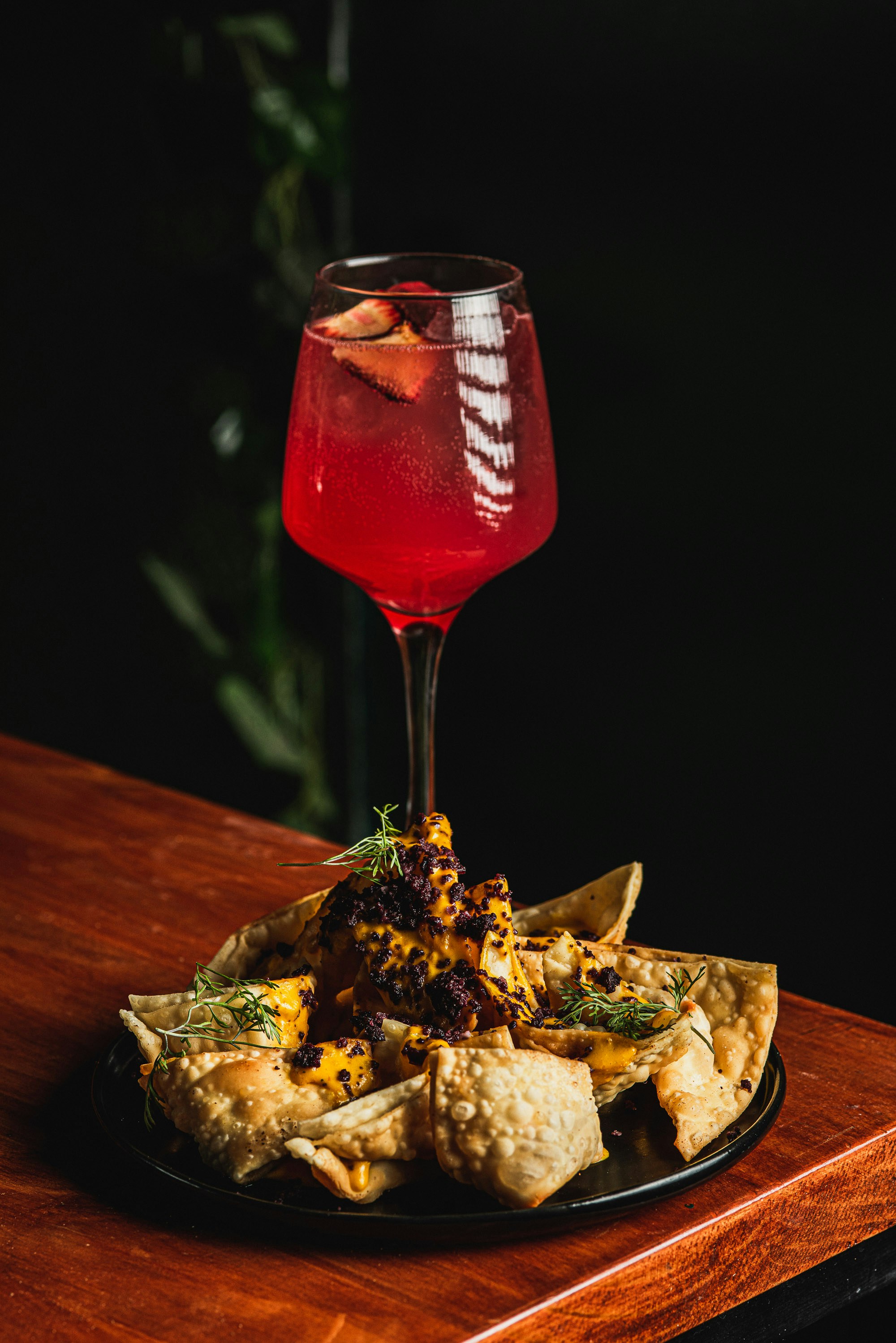 A red cocktail served with nachos on a plate