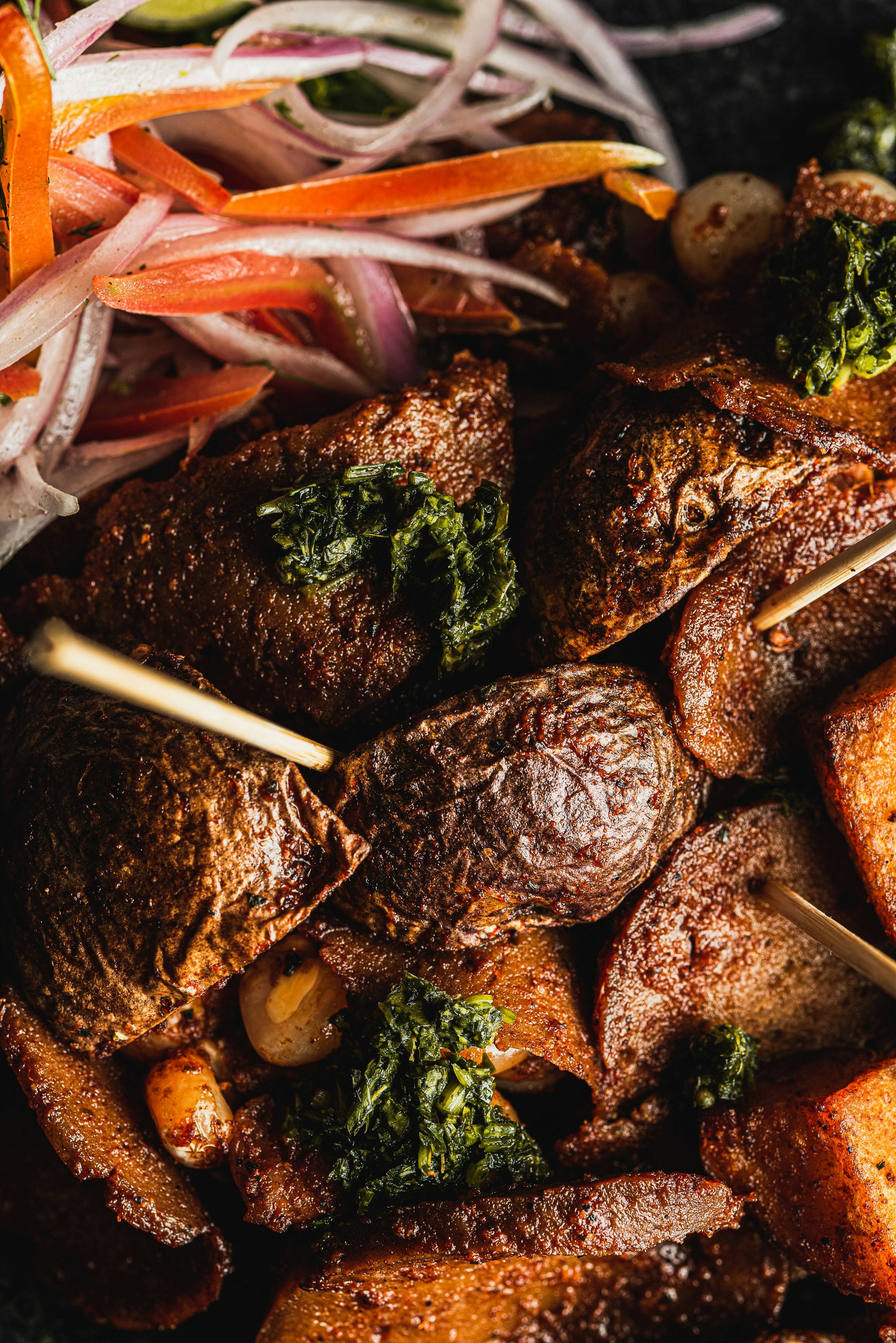 A vibrant arrangement of spiced meats and garnishes, complemented by colorful vegetables. The dish showcases a rich blend of textures and flavors.