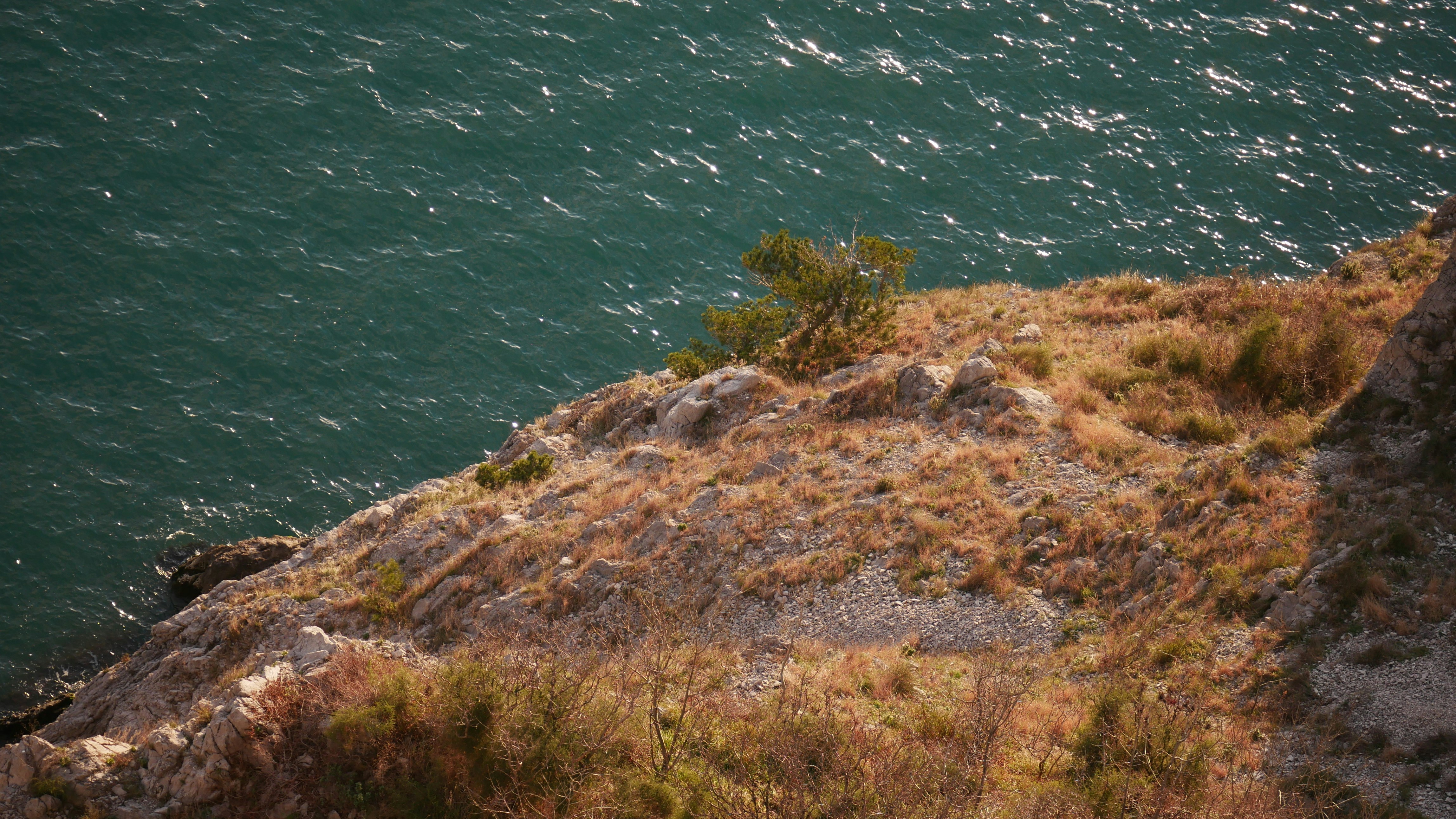 A rugged coastline meets the tranquil sea, highlighting the interplay of land and water. The vibrant hues of the landscape contrast beautifully with the deep blue ocean.