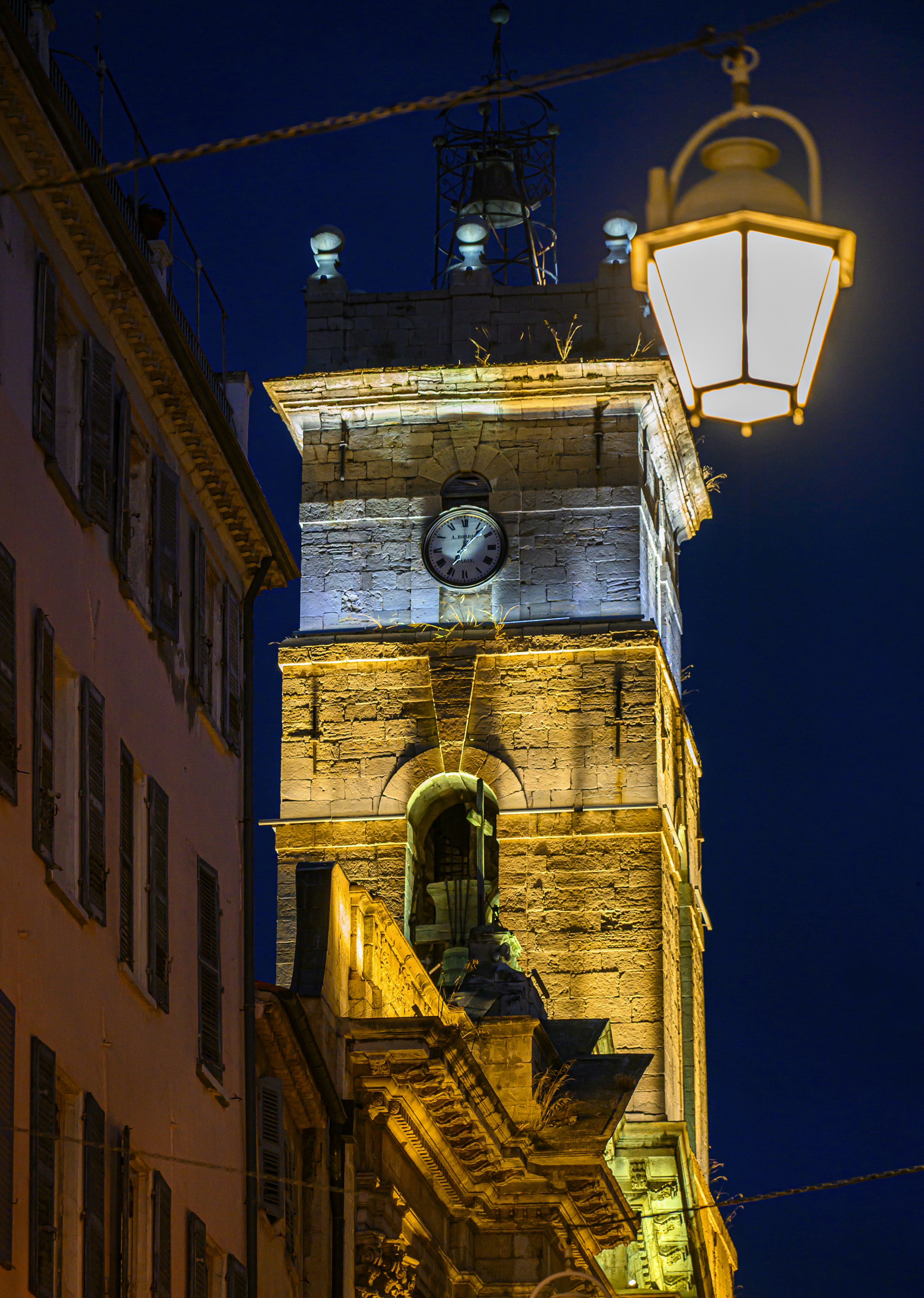 Illuminated clock tower at night with street lamp