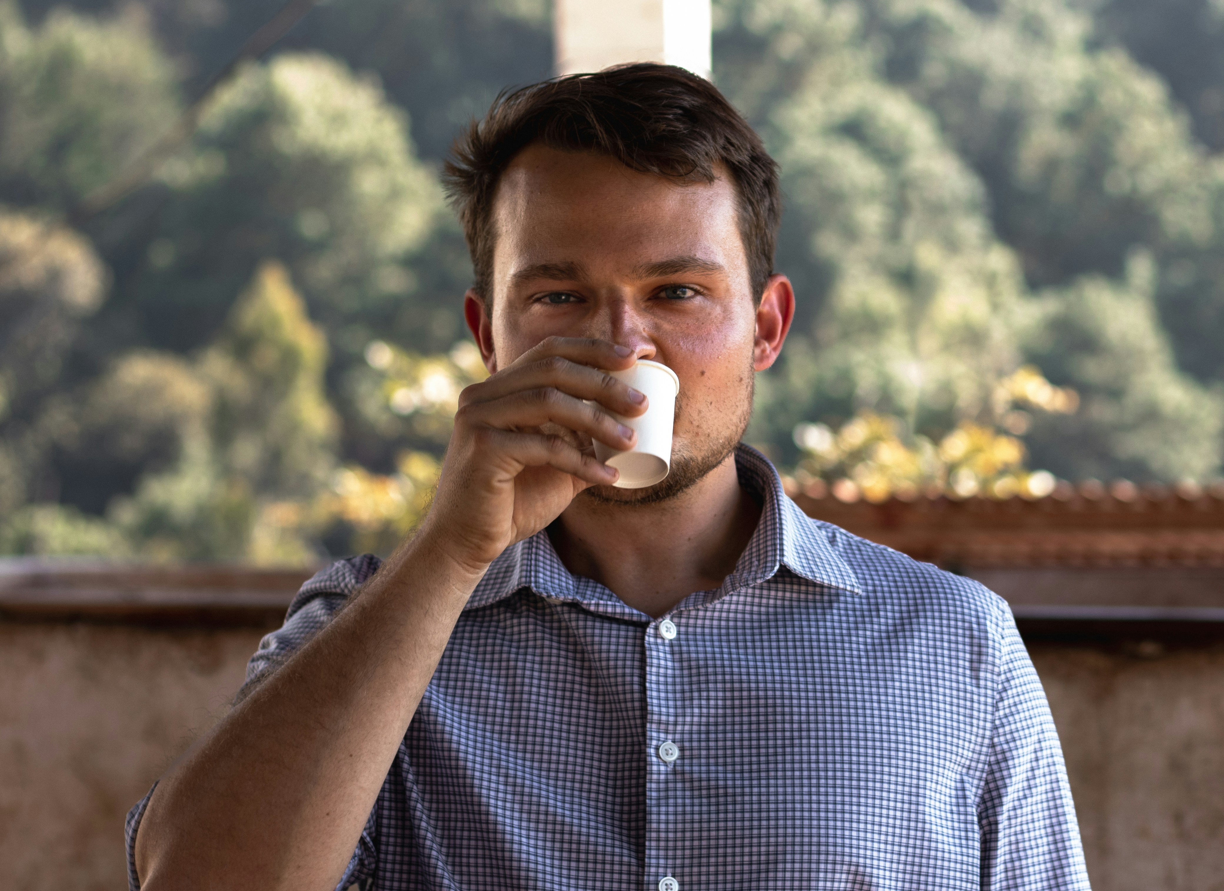 Man enjoying a drink while surrounded by a lush, natural backdrop. The scene conveys a sense of relaxation and mindfulness.