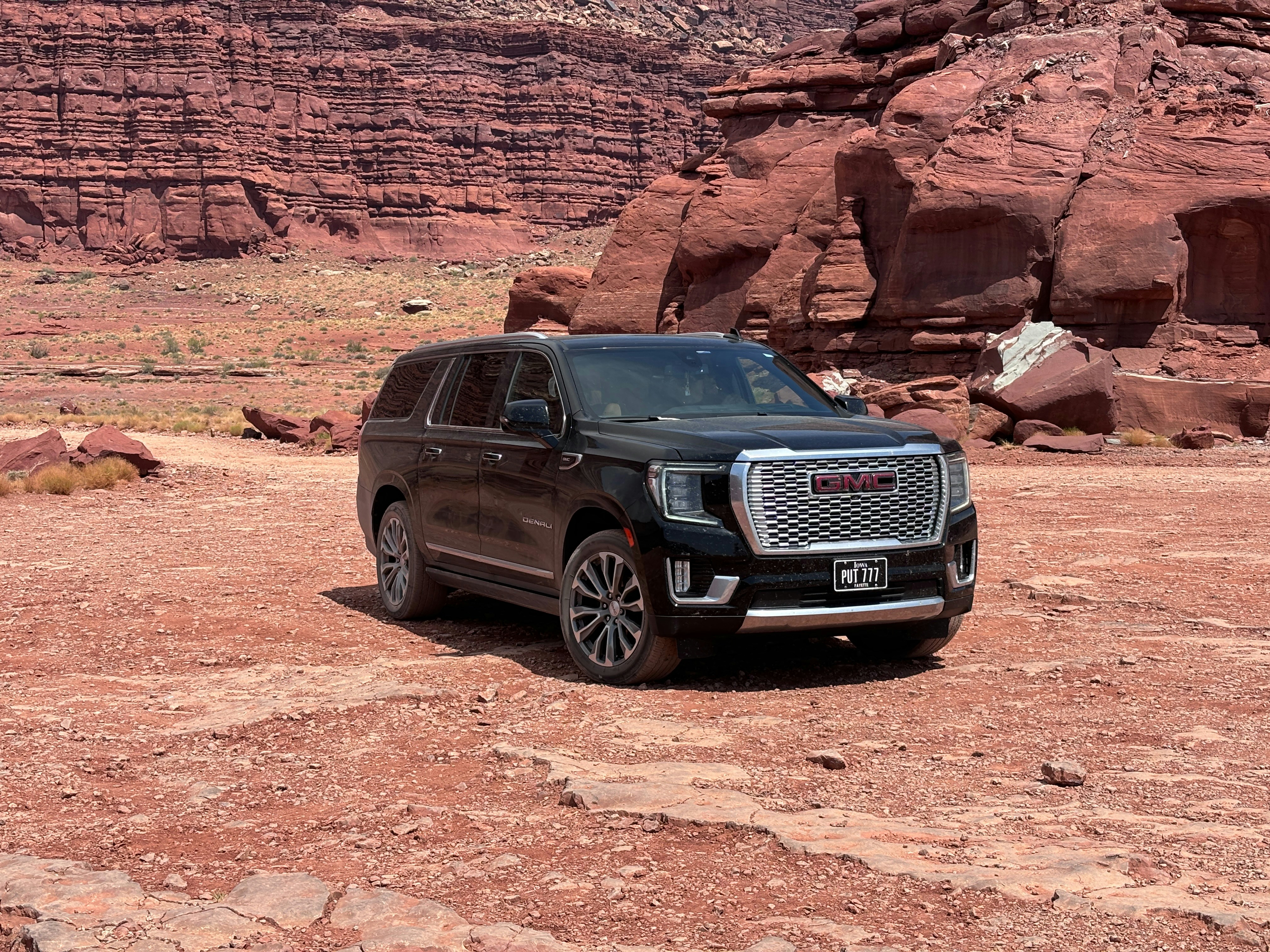 A GMC SUV positioned on rugged red rock terrain, showcasing its robust design against a striking natural backdrop.