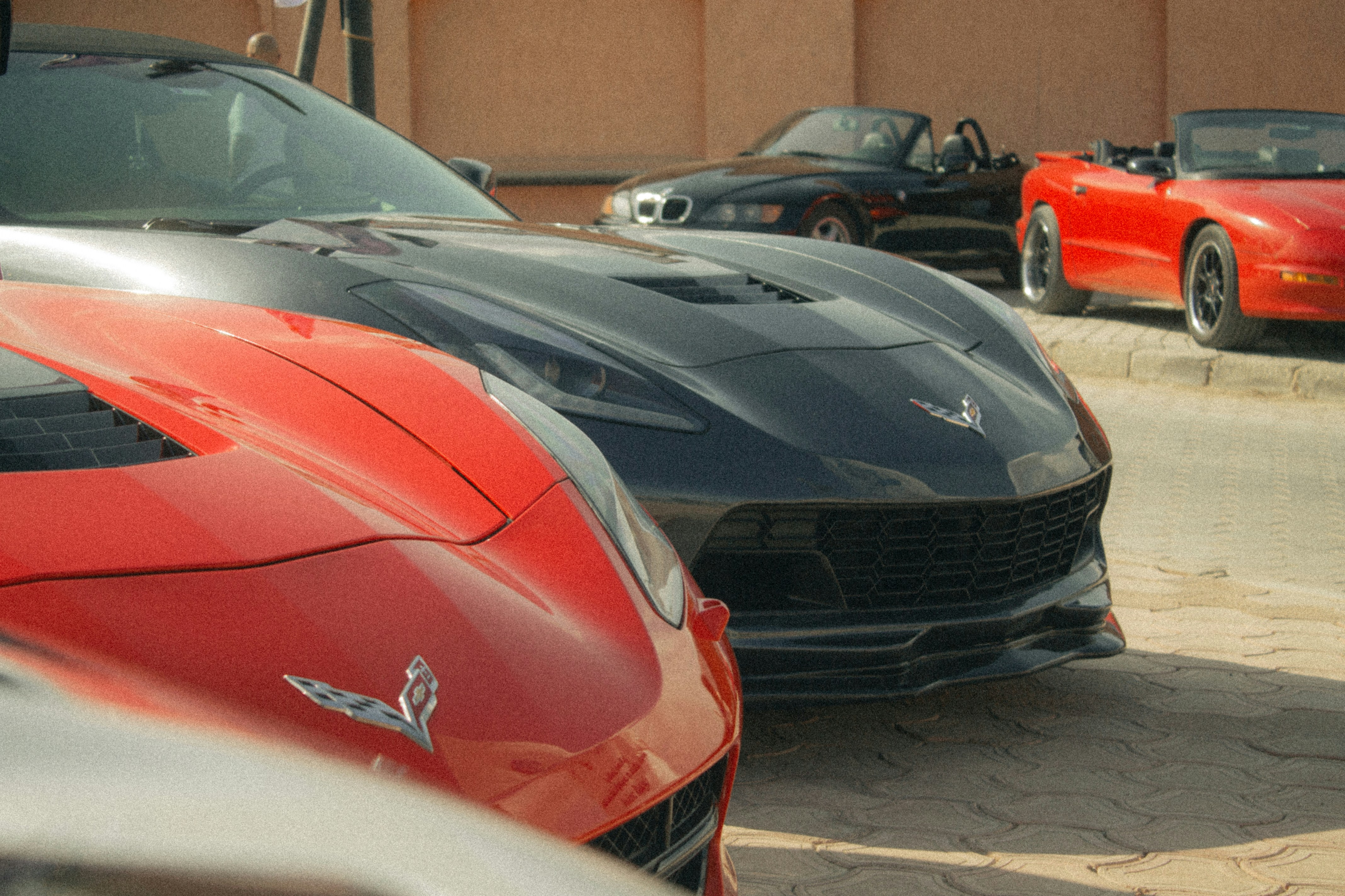 Front-Row Scarlet: The Red Corvette Leads a Quiet Parade of Parked Sports Cars