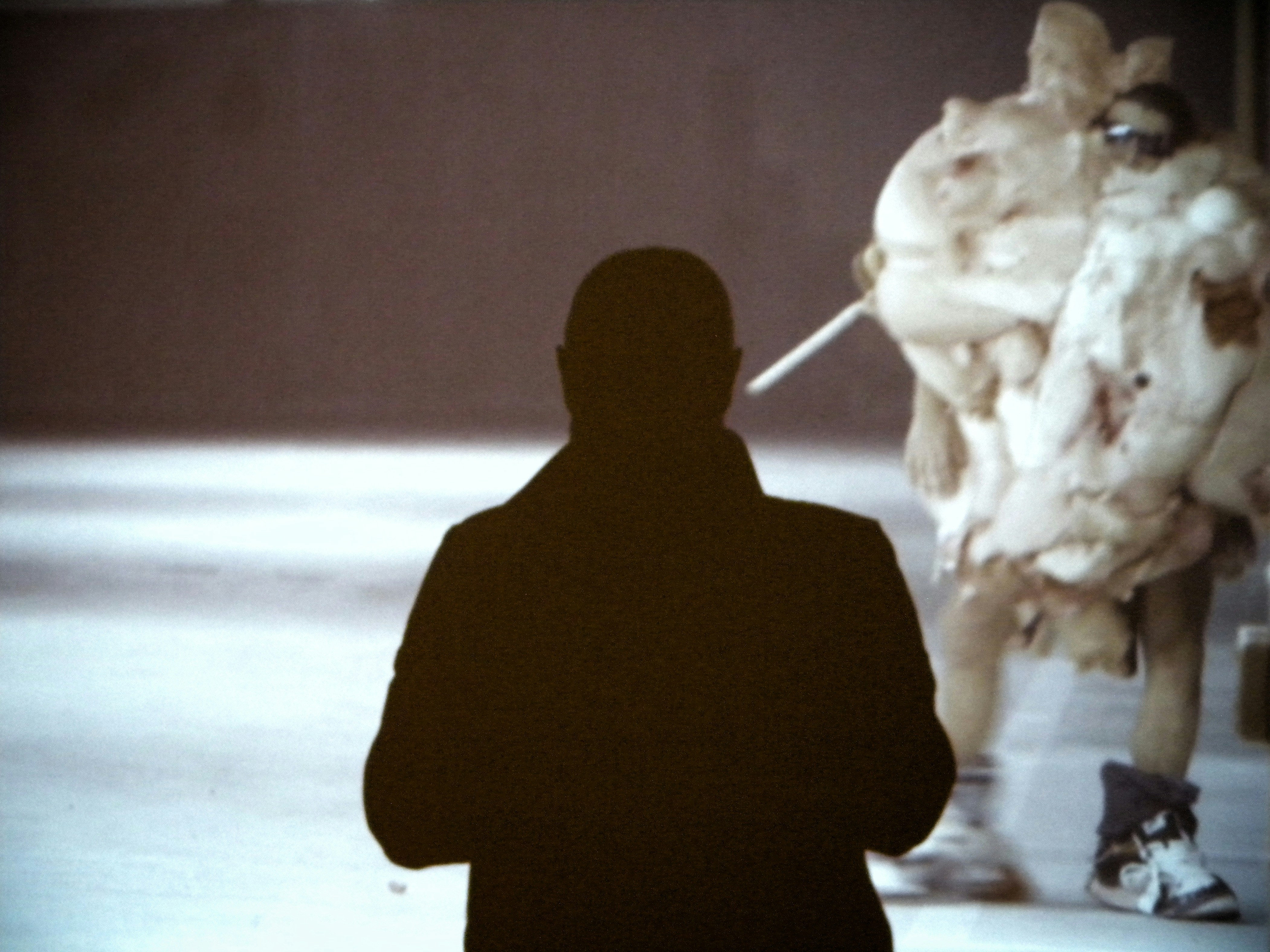 Silhouette of man watching performers in costumes.