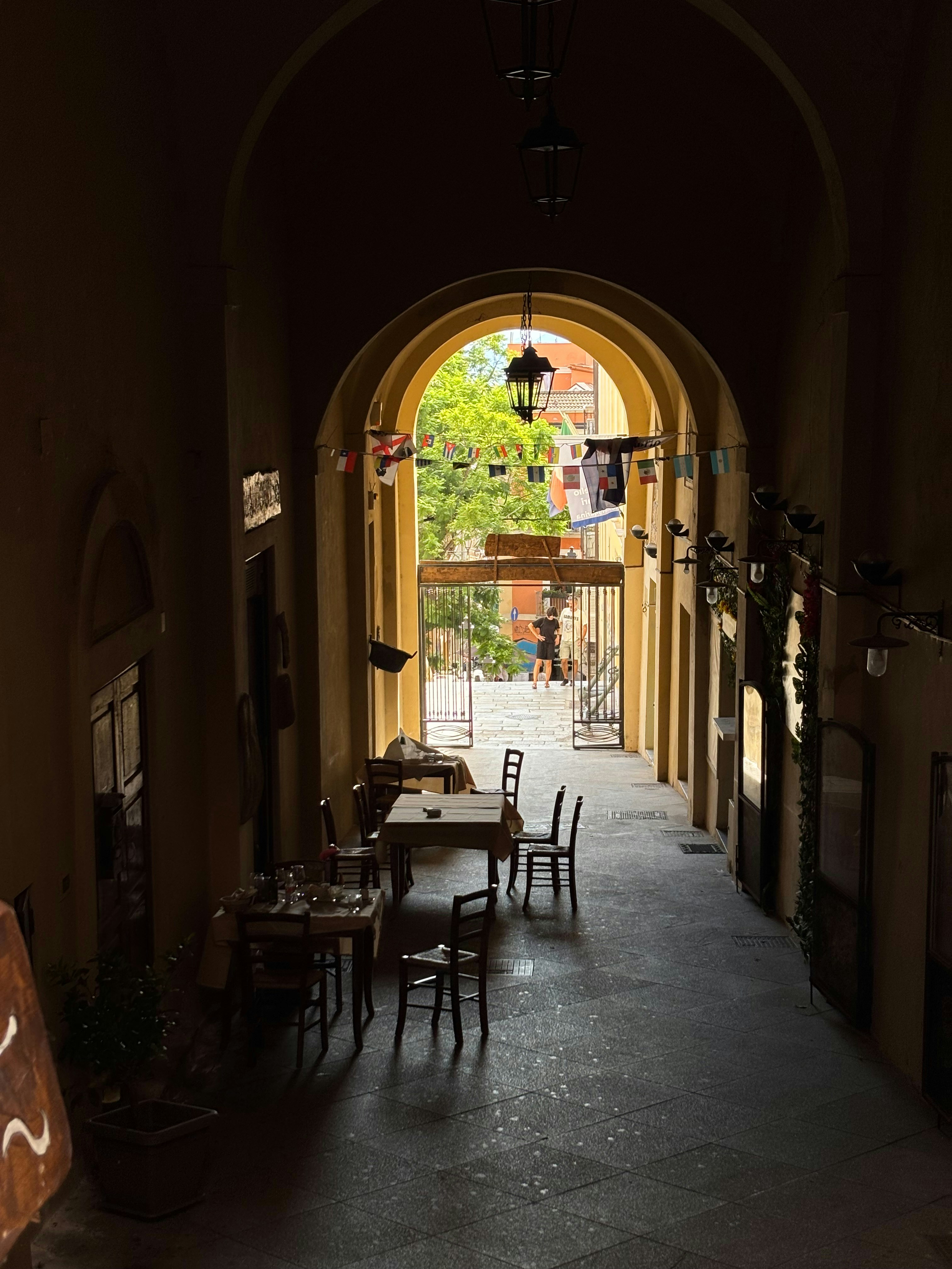Nature’s architecture meets human escape — silence, salt, and sunlight. | Empty outdoor cafe seating in arched walkway