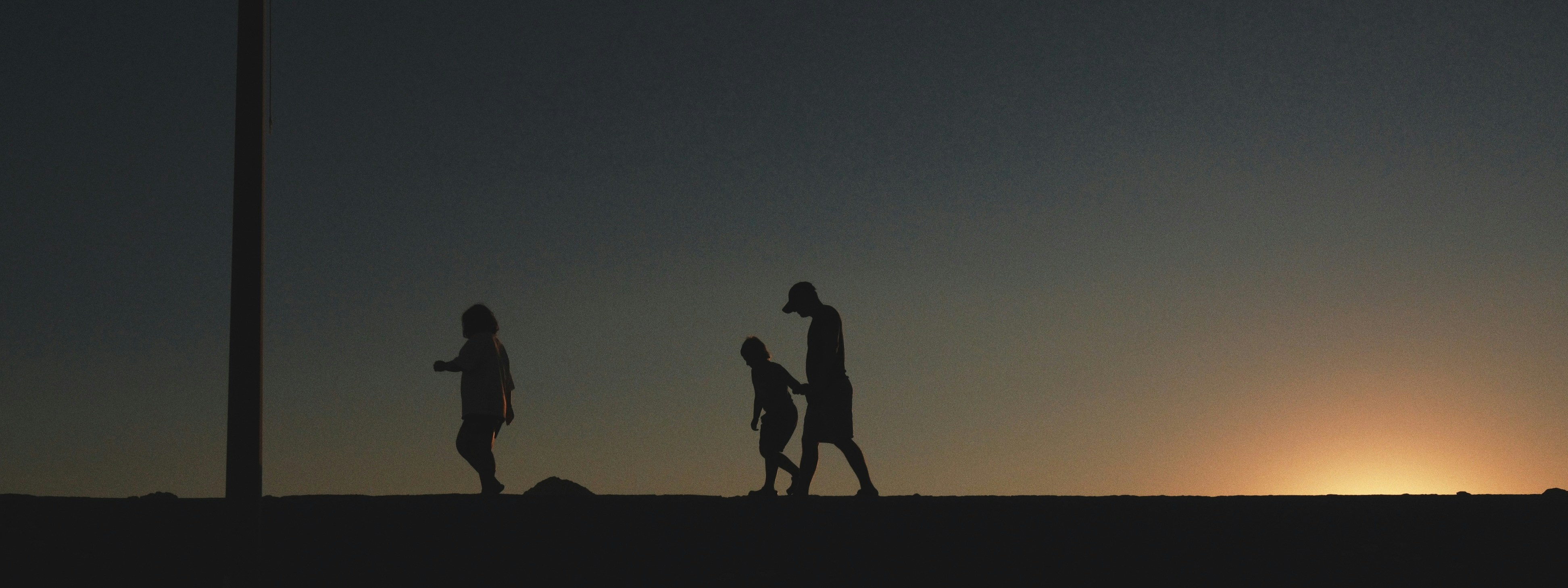 Silhouettes of people walking at sunset