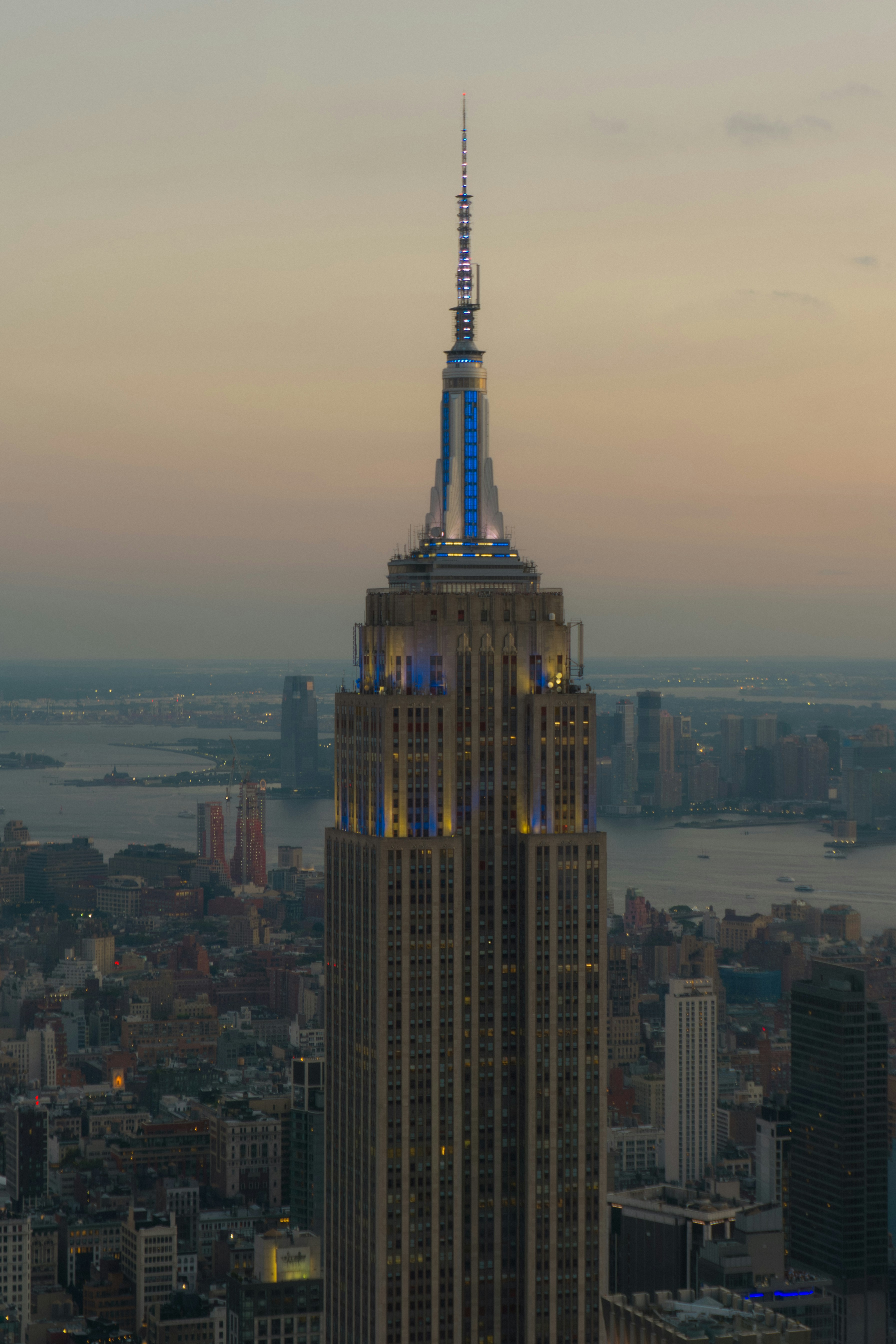 Empire state building illuminated with blue lights at dusk