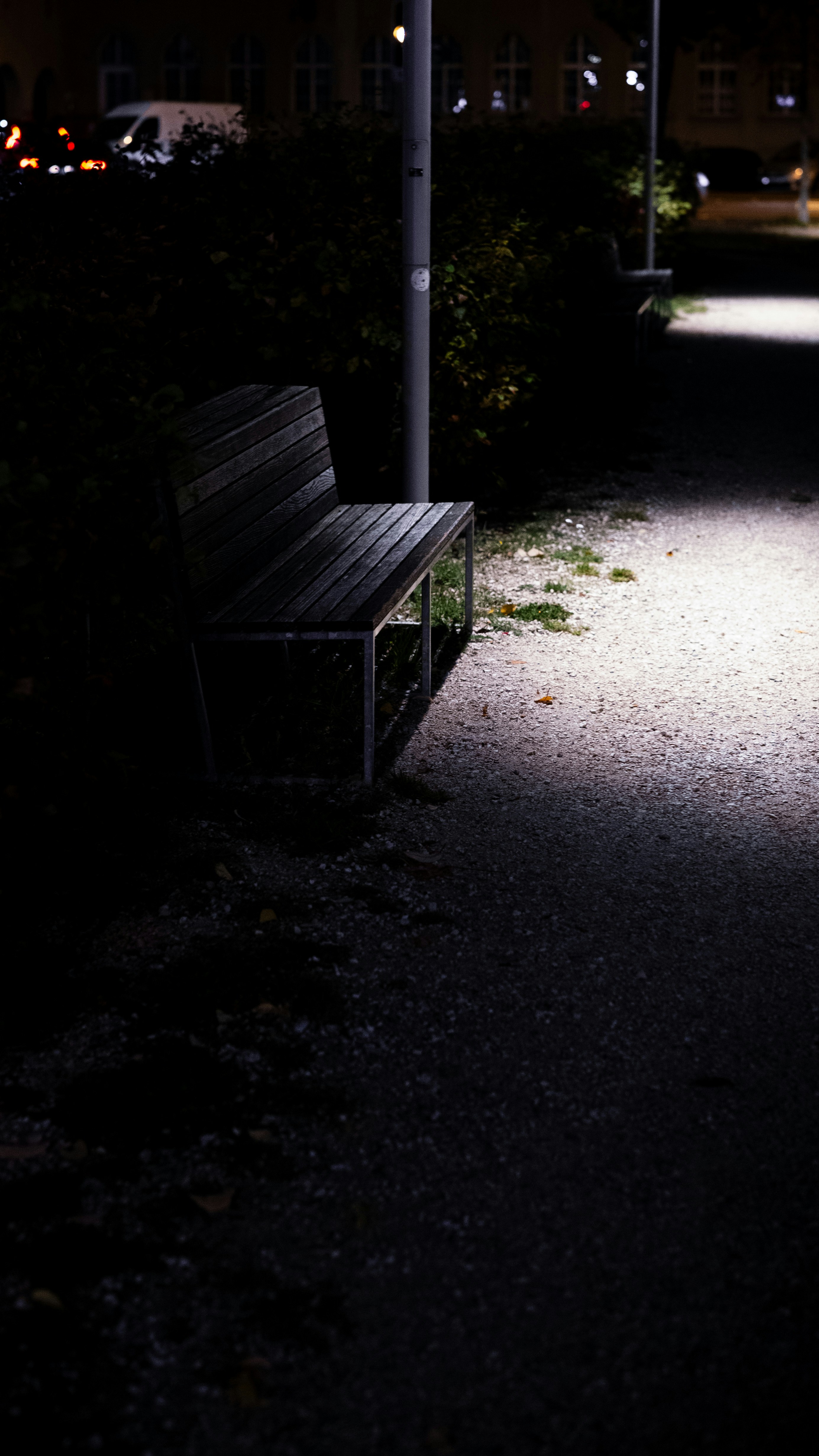 A wooden bench sits on a path at night.