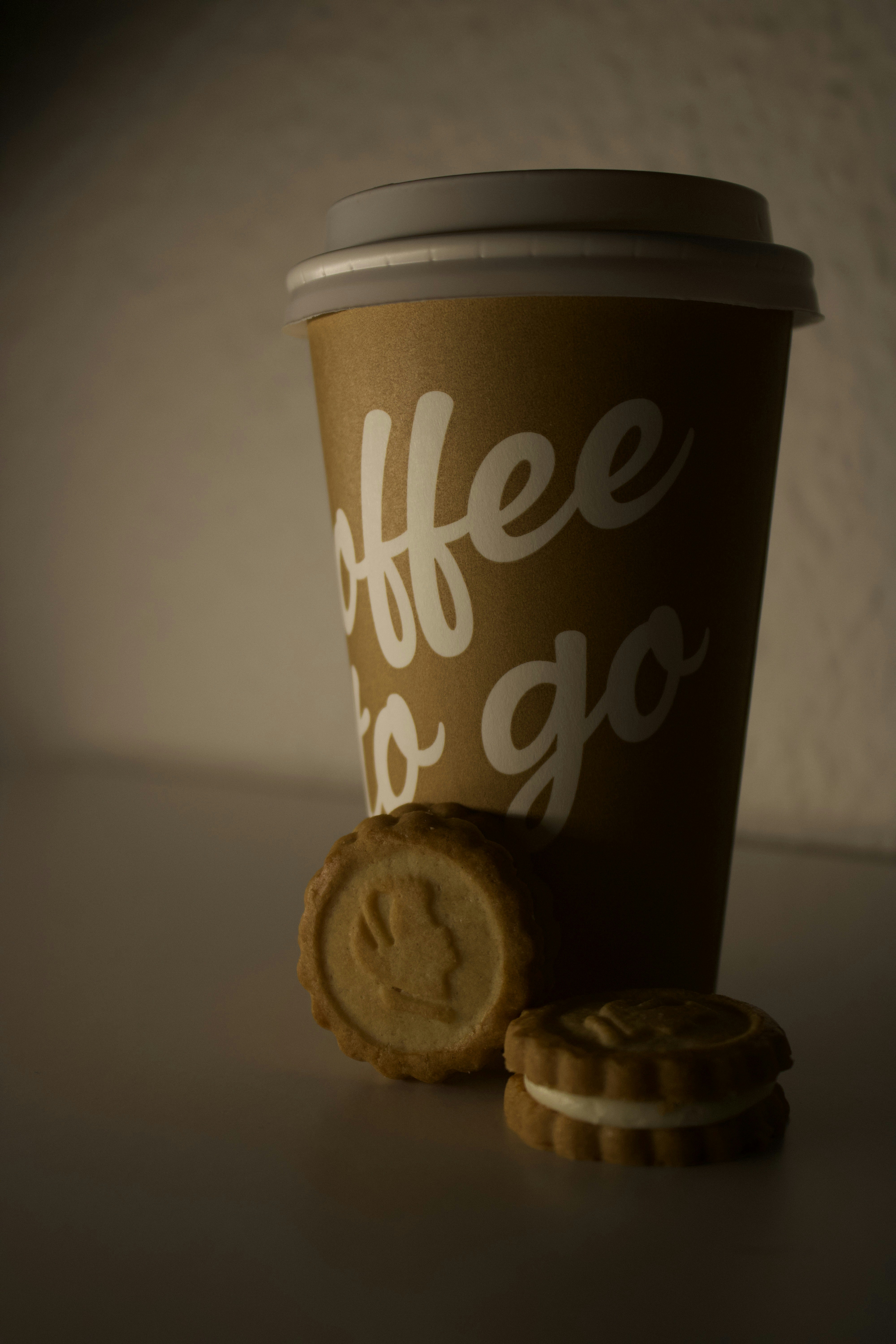A disposable coffee cup with two cookies.
