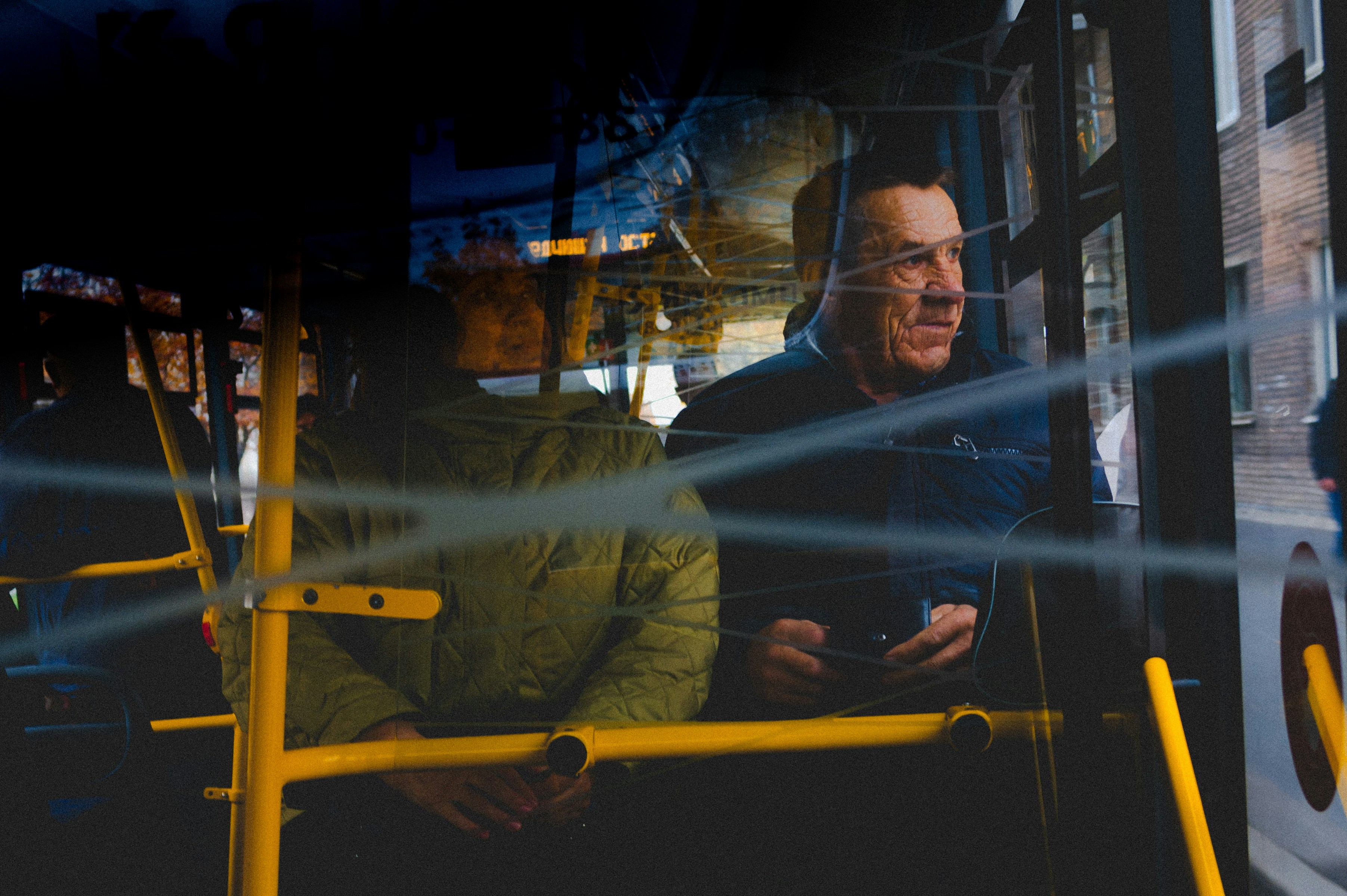 Man looking out bus window with phone