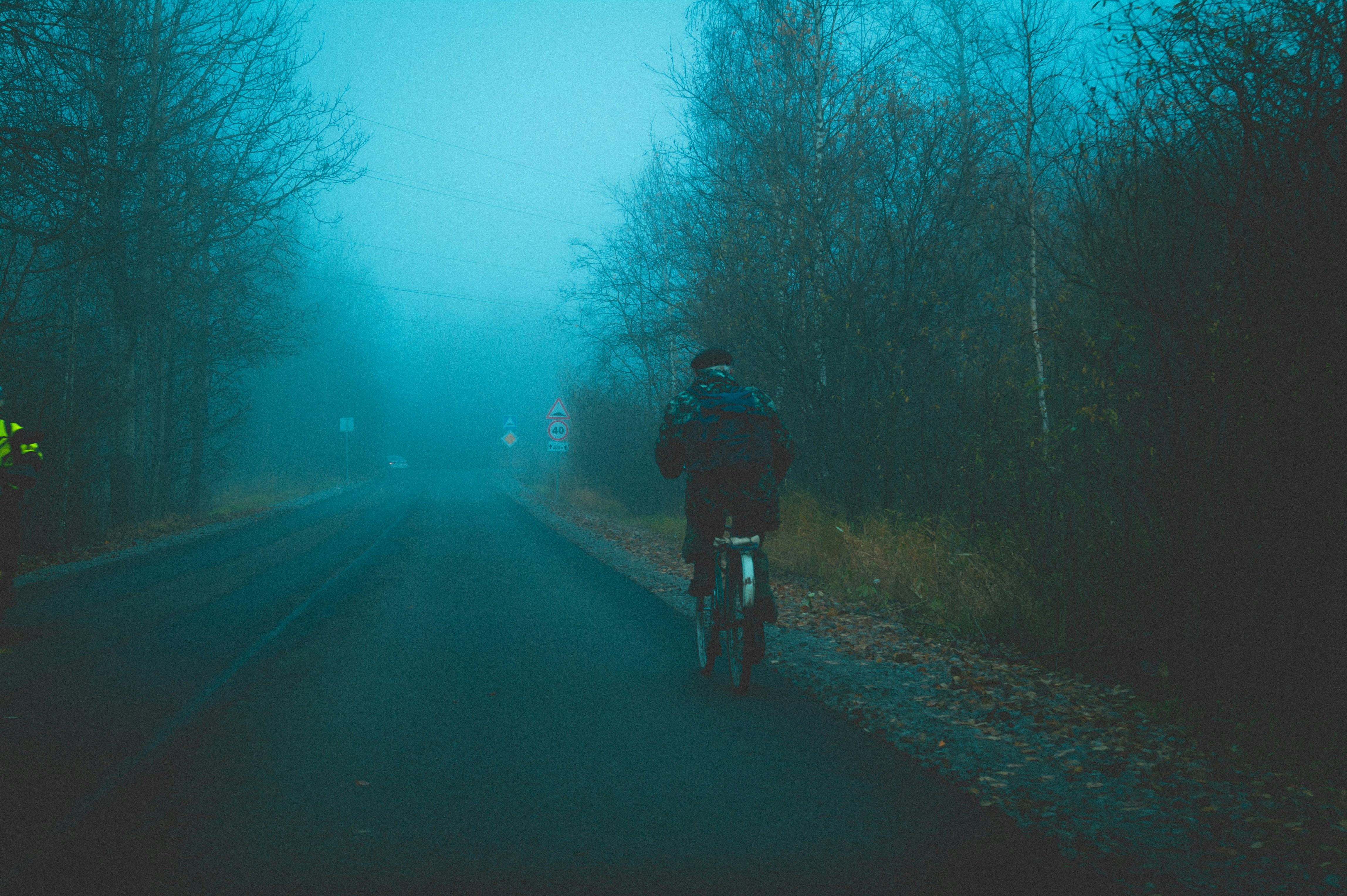 Person rides bicycle on foggy road at dusk