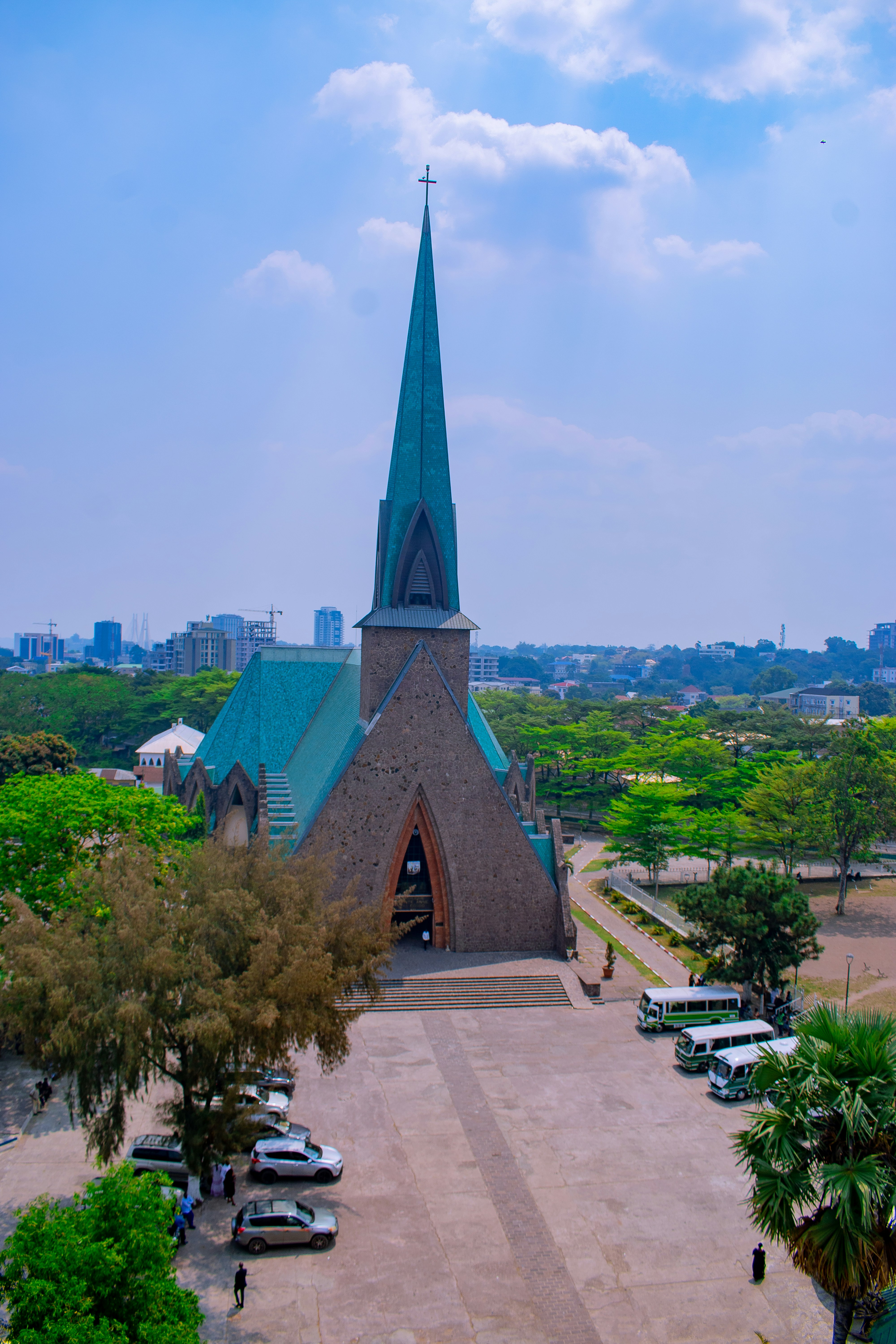 Basilique Sainte Anne du Congo | Stone church with green steeple and surrounding trees.