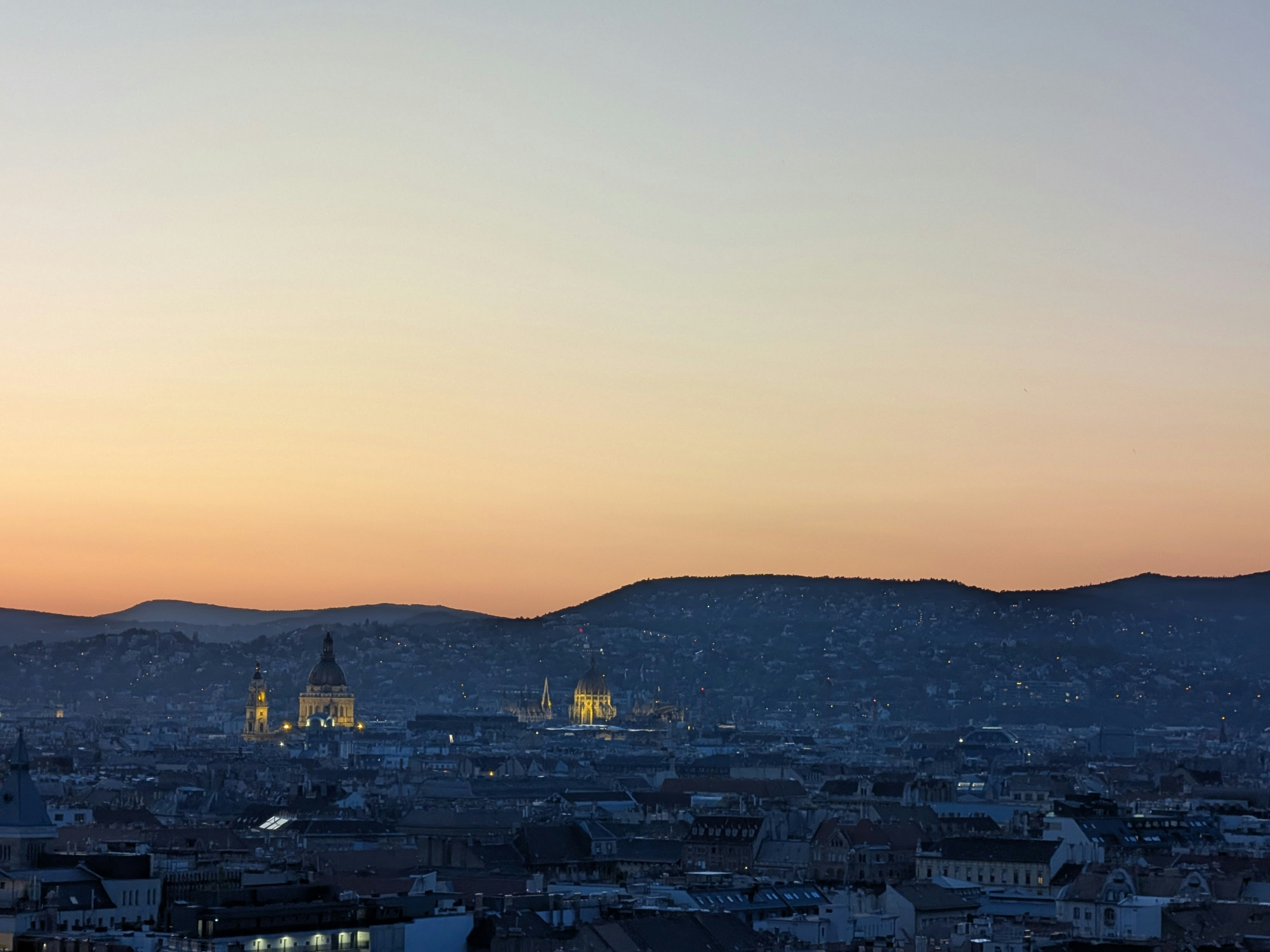 Silhouetted cityscape at twilight with historic buildings illuminated against a fading sky.