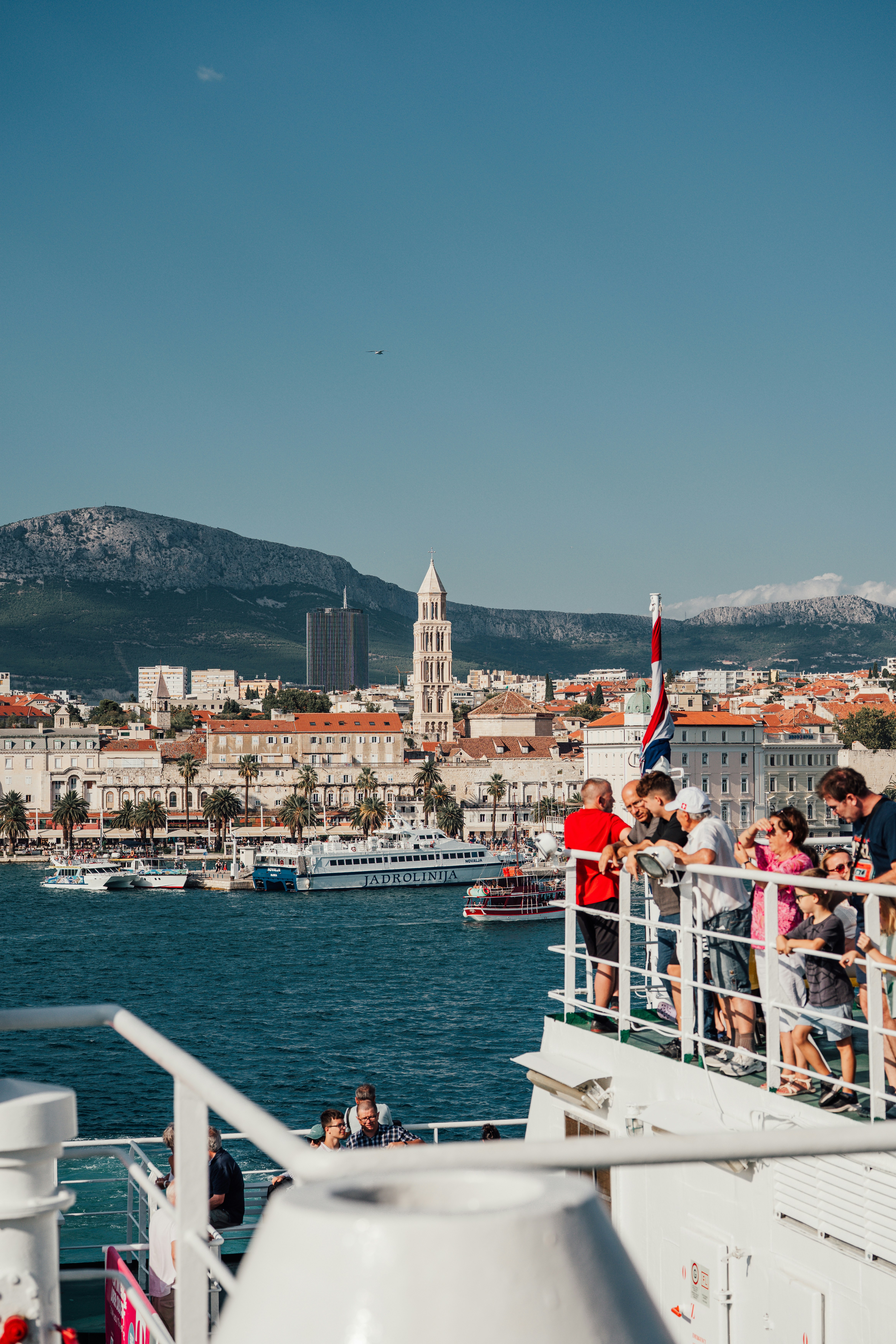 People on a ferry looking at a coastal city.