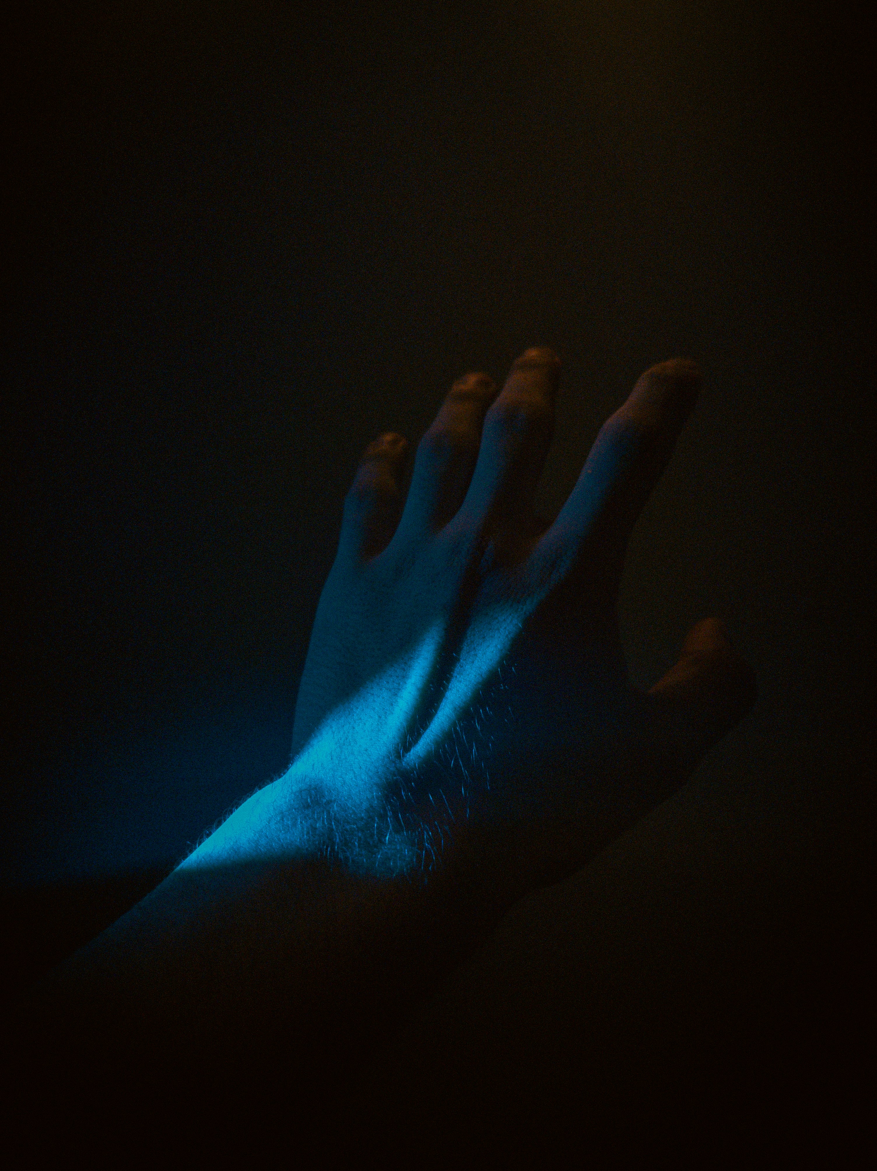 Hand in dark | A hand illuminated by blue light in darkness.