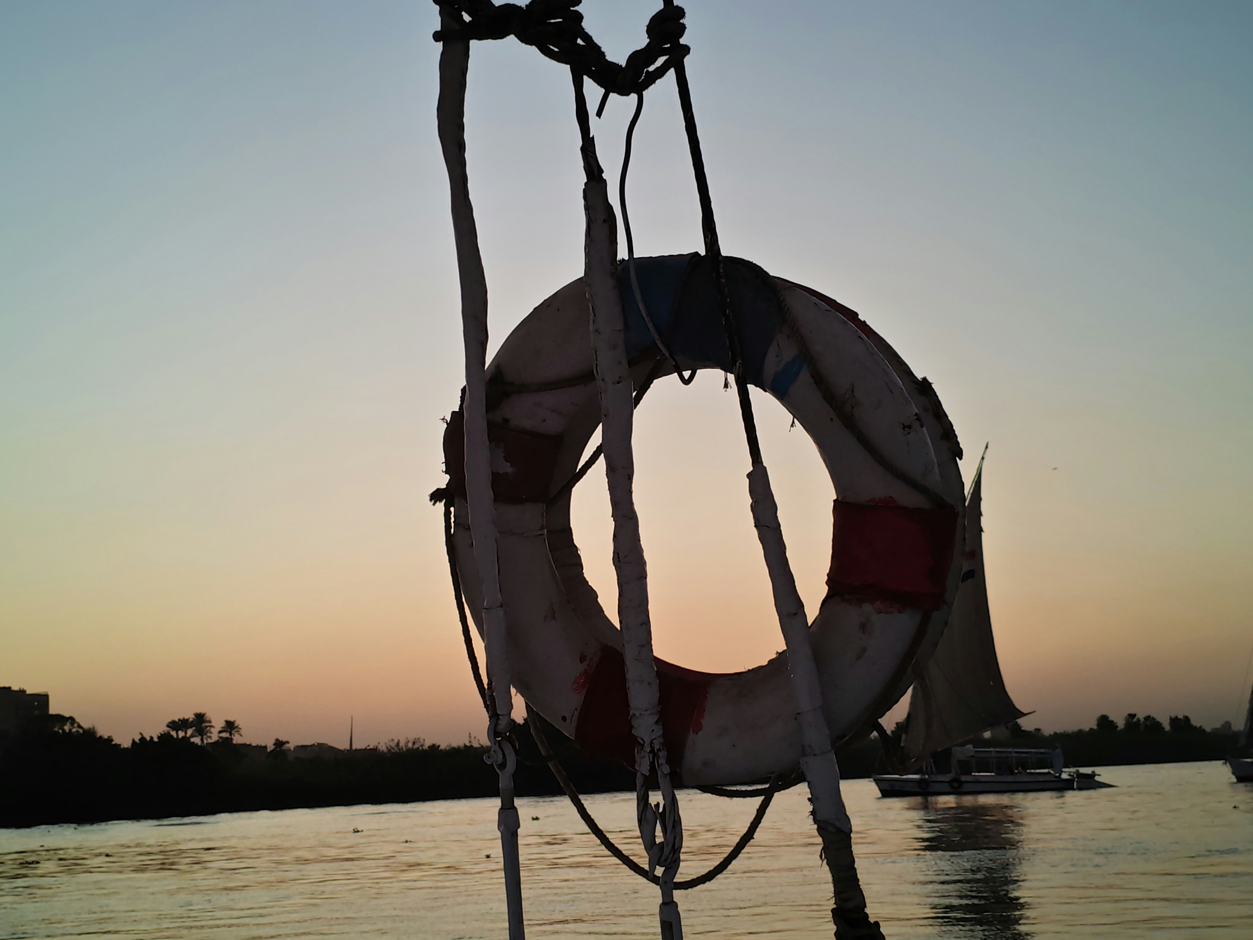 Lifebuoy suspended against a serene sunset backdrop, symbolizing safety on the water. The horizon reflects soft hues of twilight.