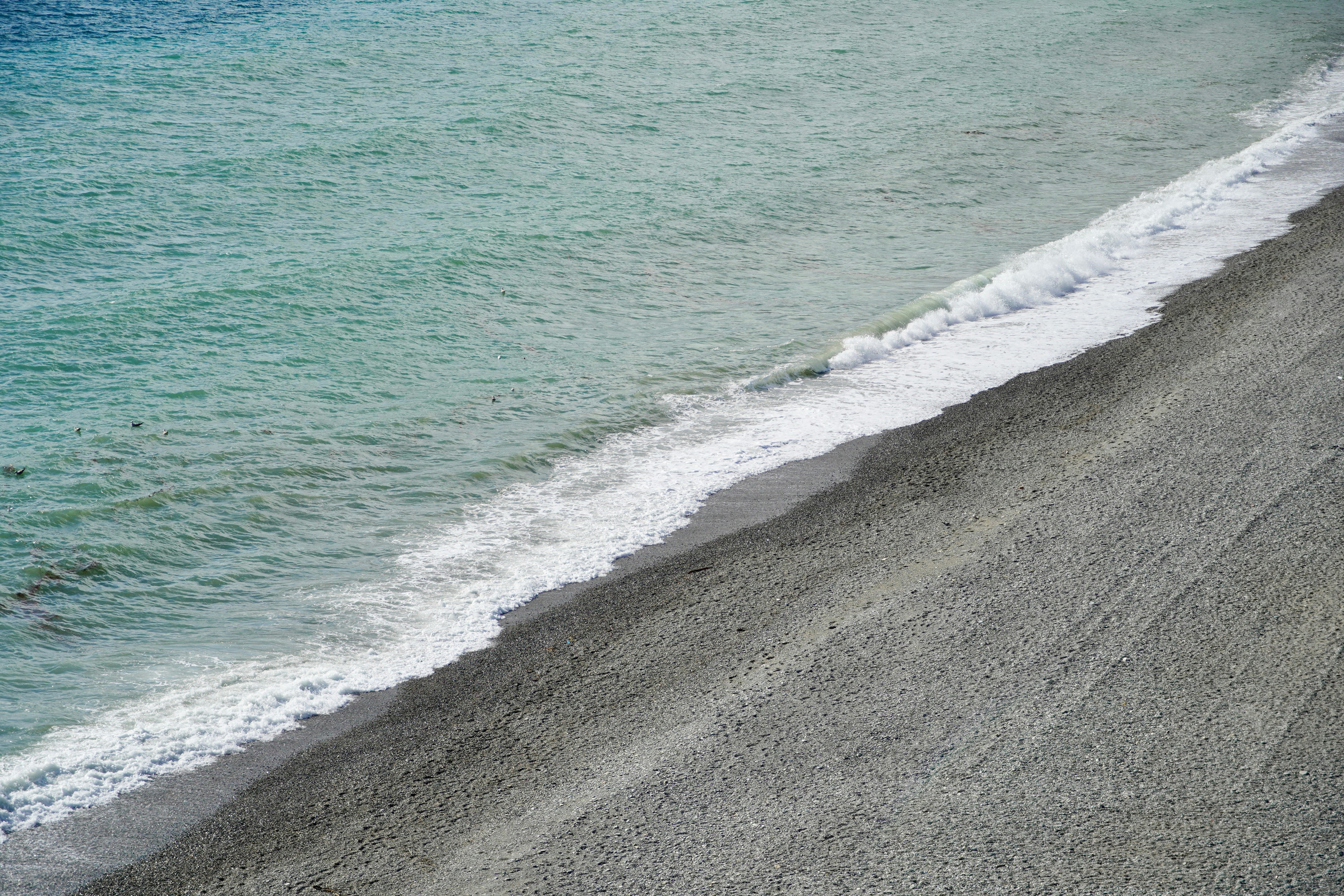 Gentle waves lapping against a pebbled beach, showcasing the interplay of water and land. The serene coastal scene invites tranquility.