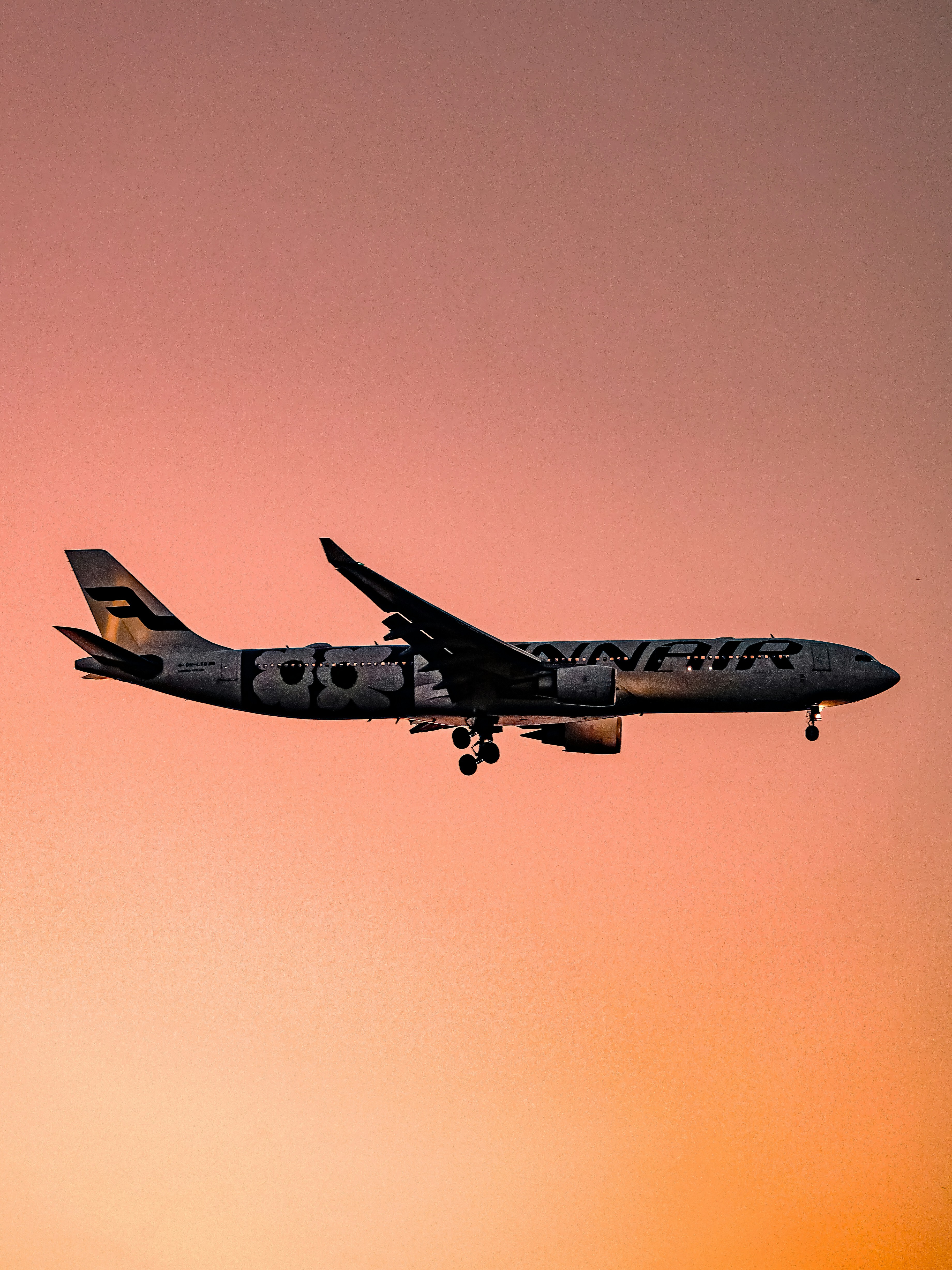 Airplane descending through a gradient sky at sunset, showcasing its silhouette against vibrant hues.