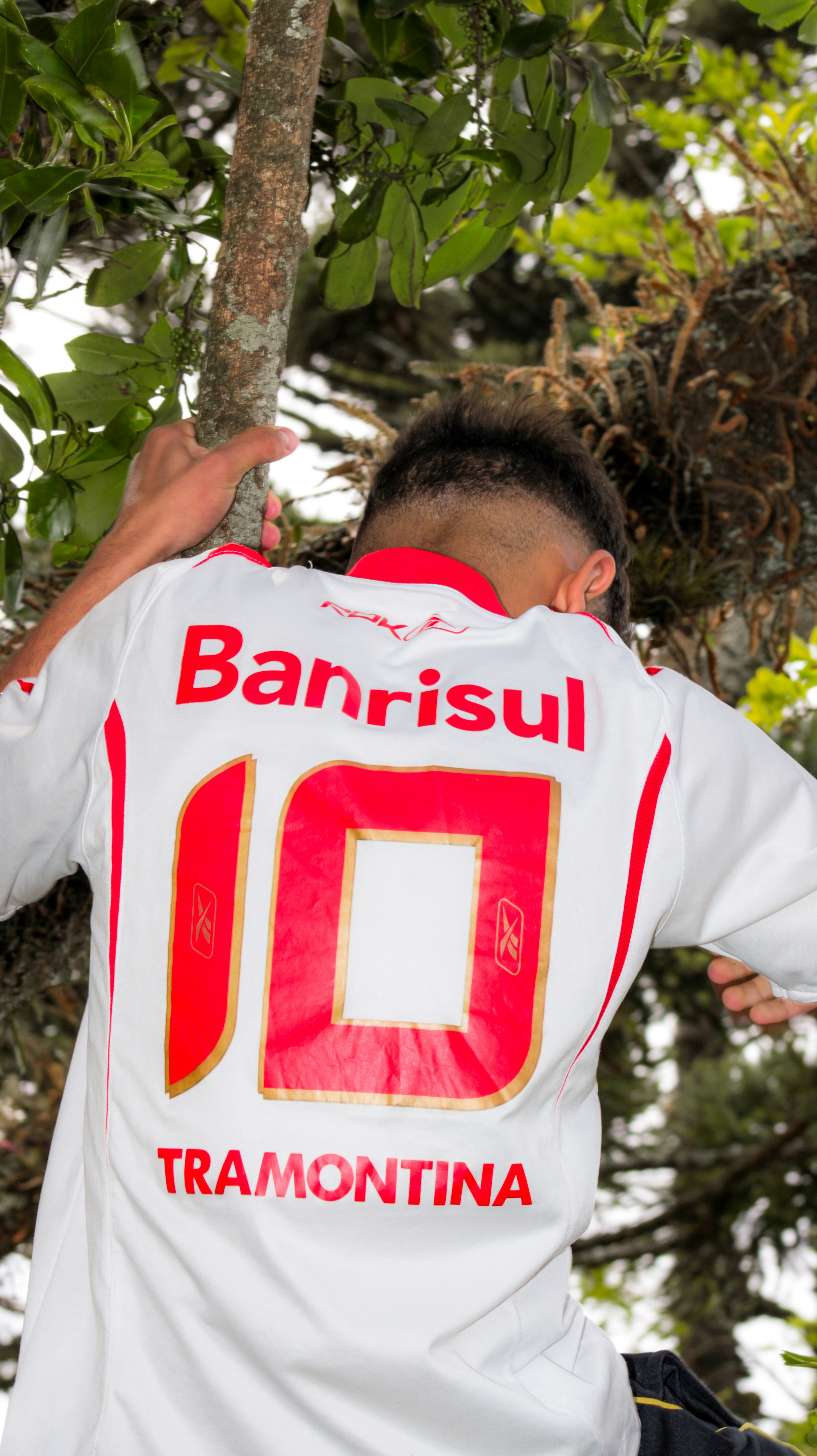 Back View of a Soccer Player Climbing Amid Green Canopy