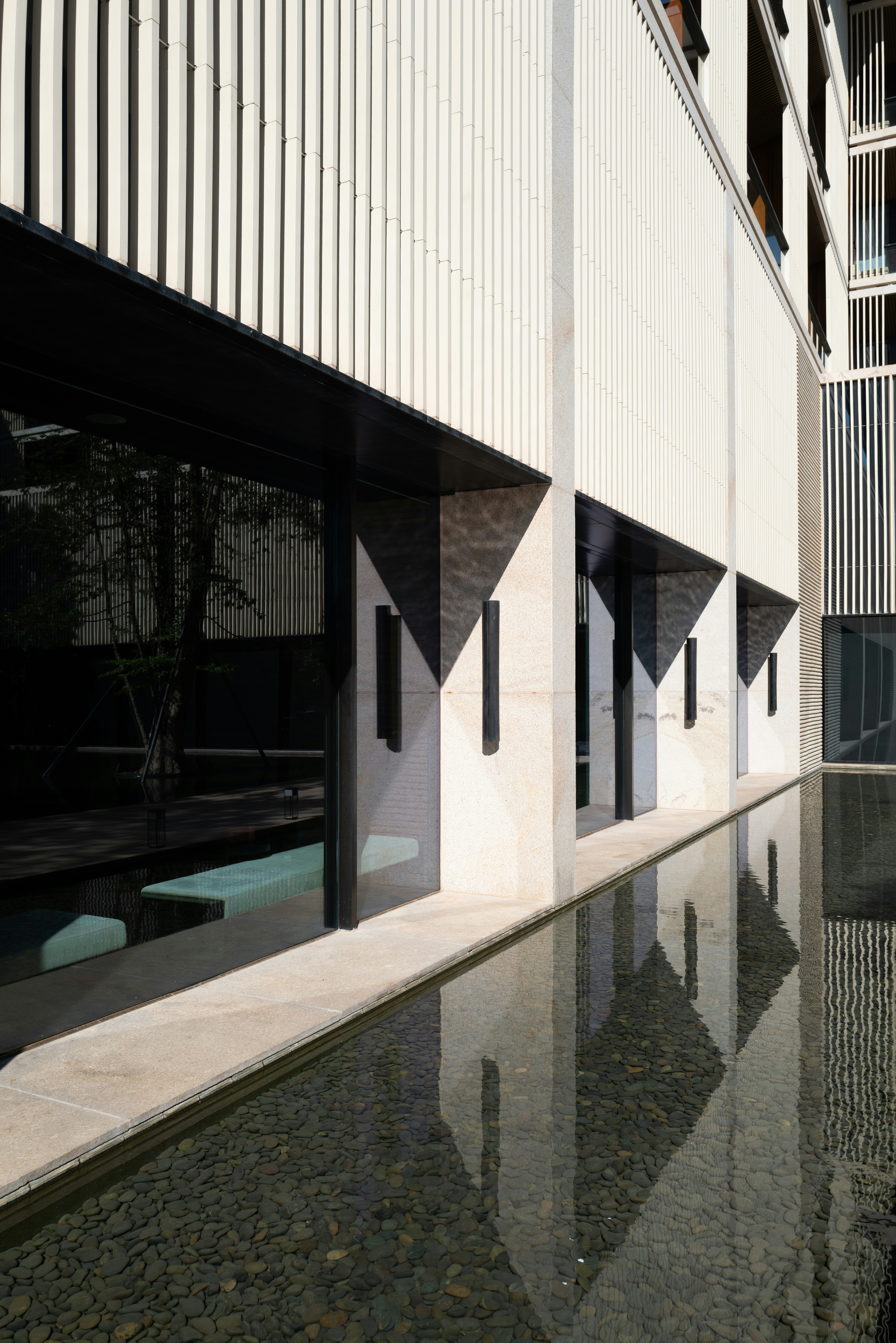 Reflected Geometry: Vertical Fins and Quiet Water Along a Modern Facade