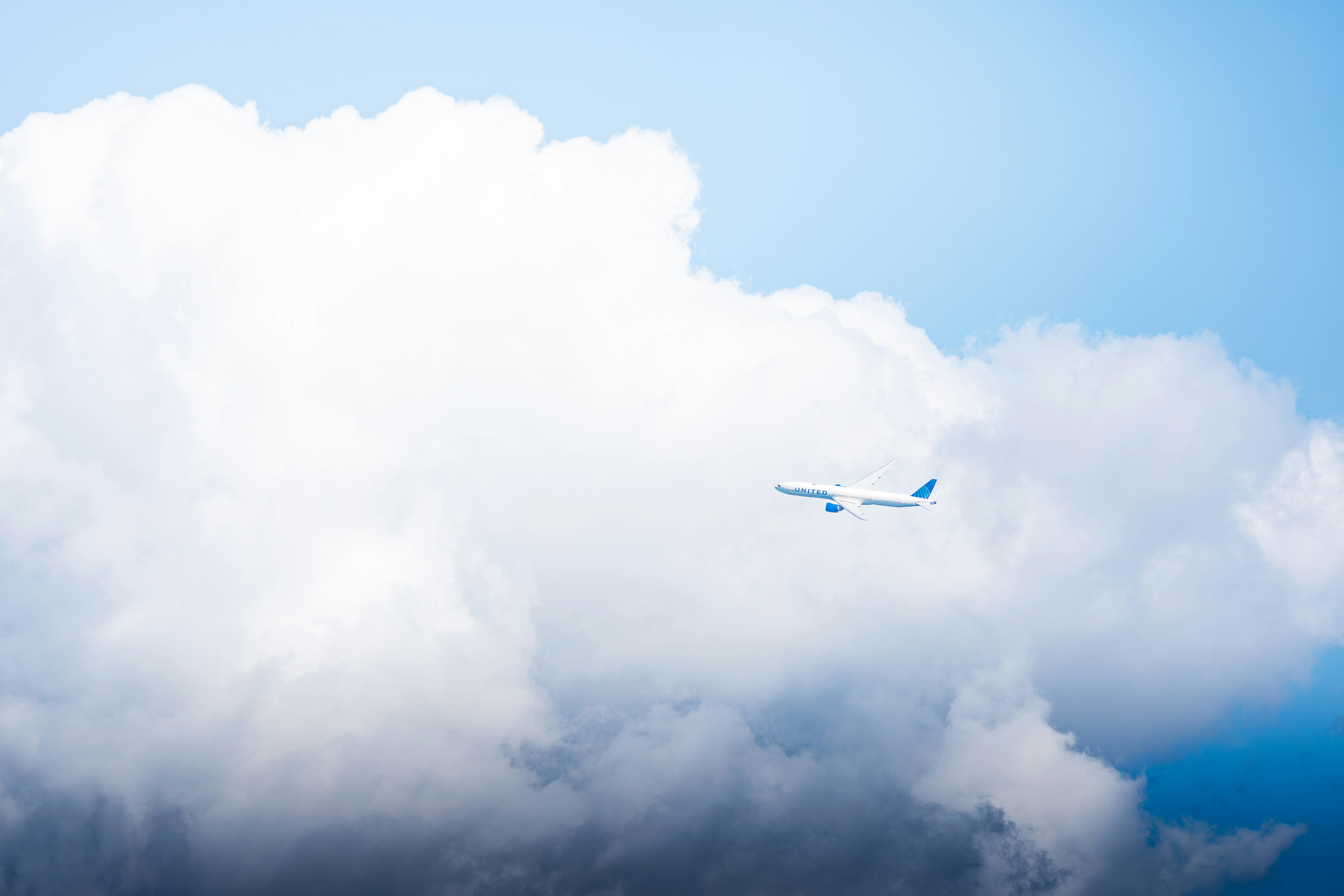 United Airlines Boeing 777 passing over clouds during its demo performance for SF Fleet Week 2025