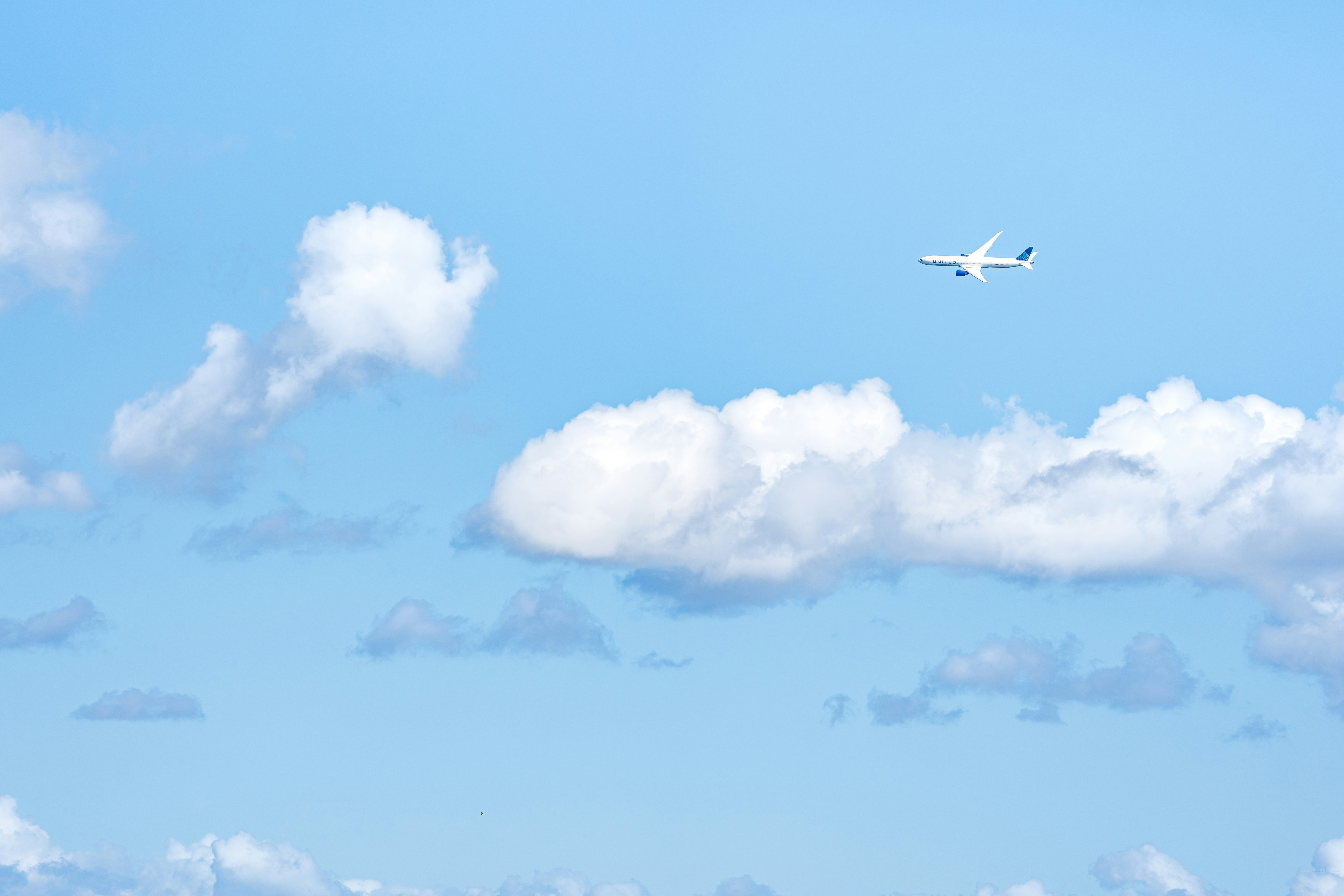 United Airlines Boeing 777 passing over clouds during its demo performance for SF Fleet Week 2025