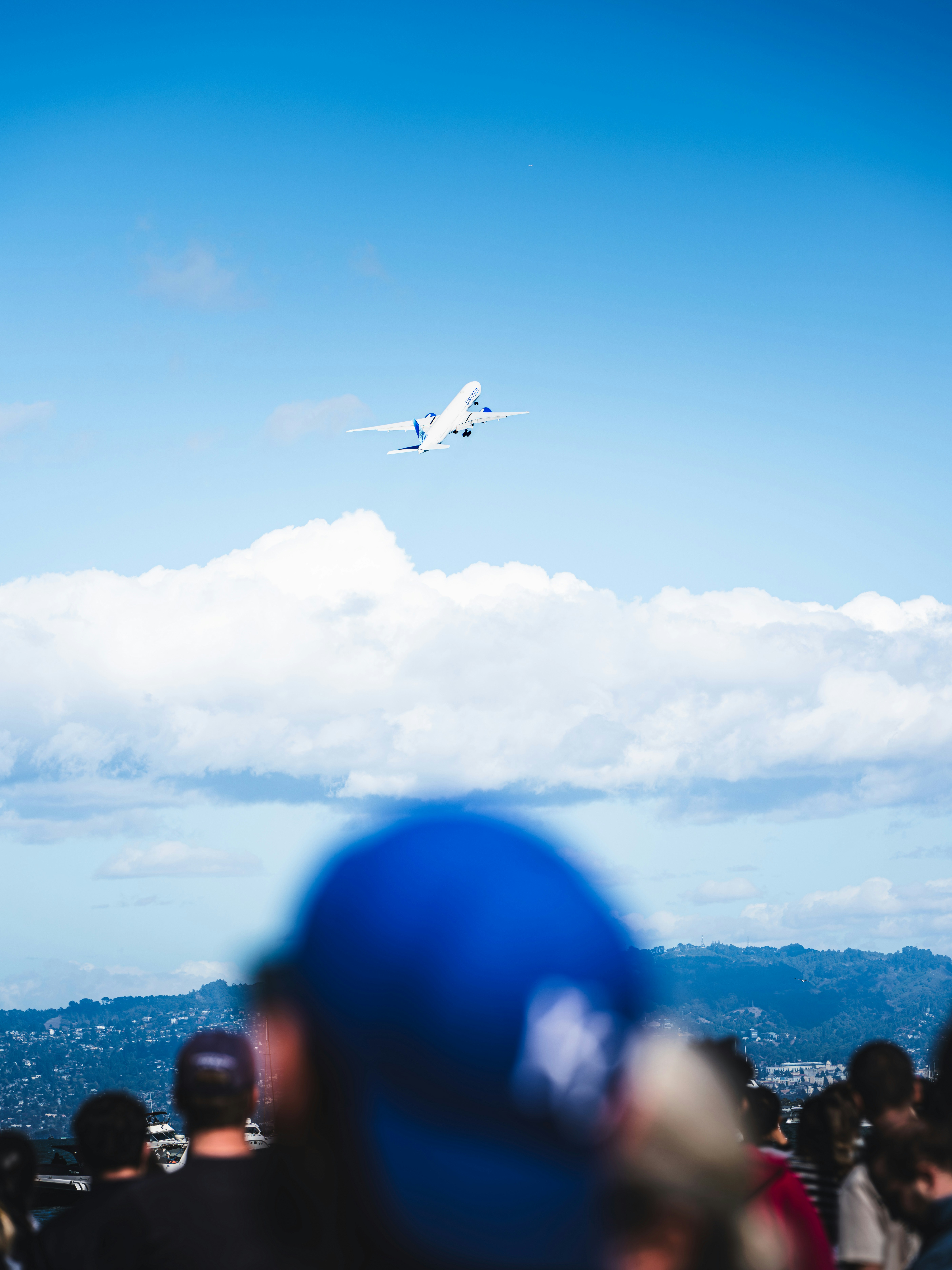 Airplane taking off against a backdrop of clouds and spectators at an airshow. 