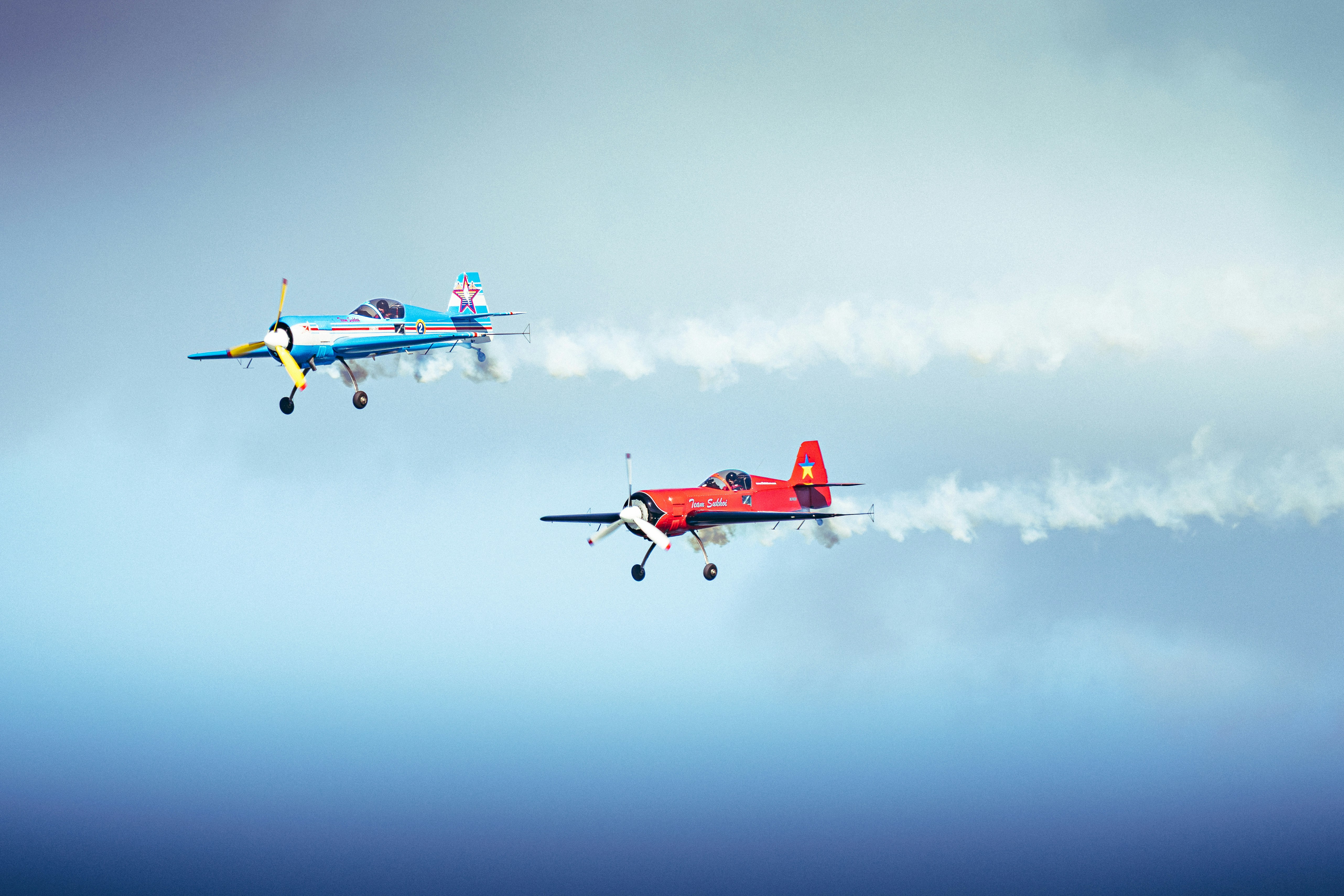 Red and Blue Aerobatic Duo Carves Smoke Arcs Across a Clear Sky