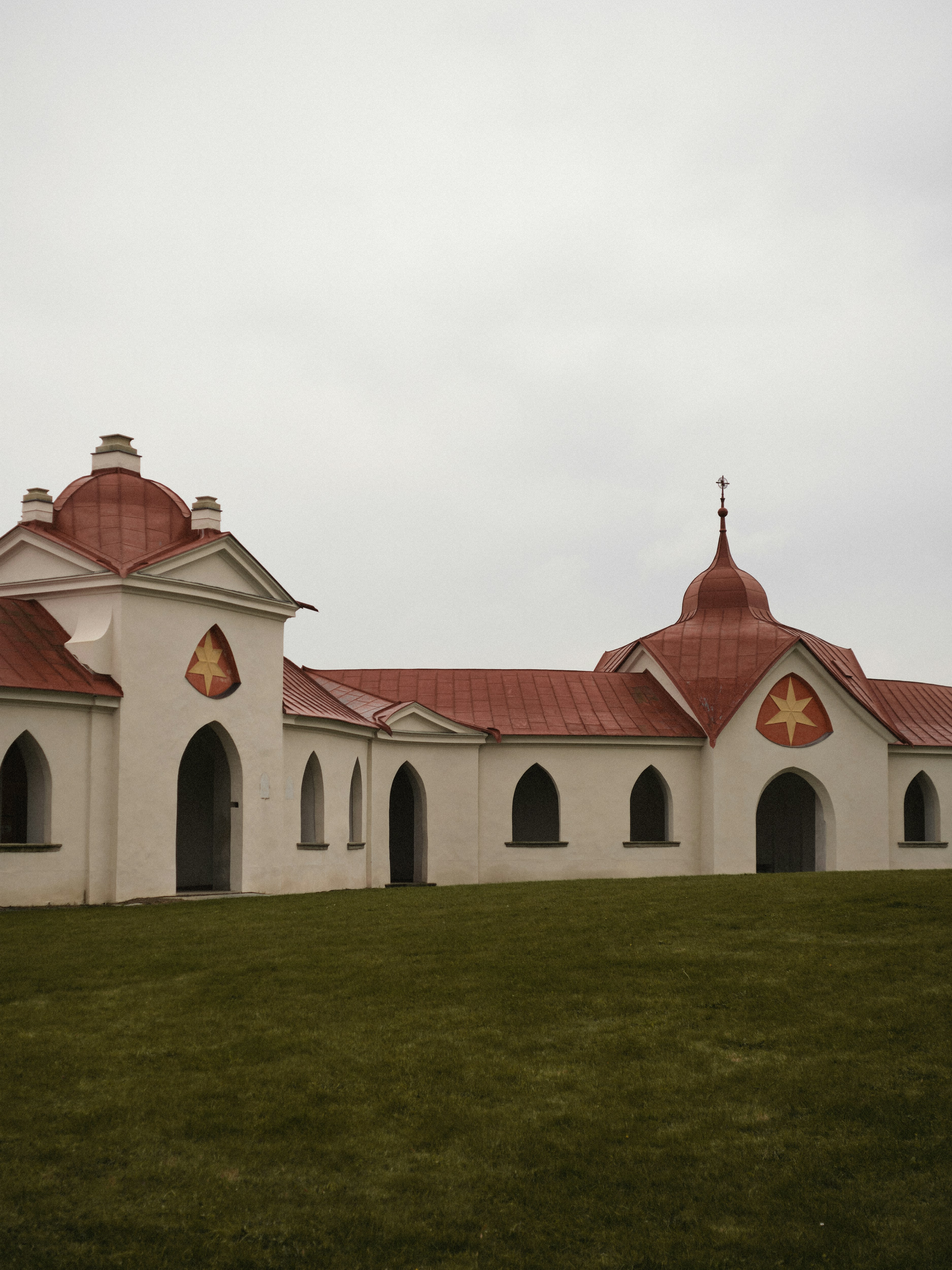 Starred Arches Along a Red-Roofed Arcade Under a Quiet Gray Sky