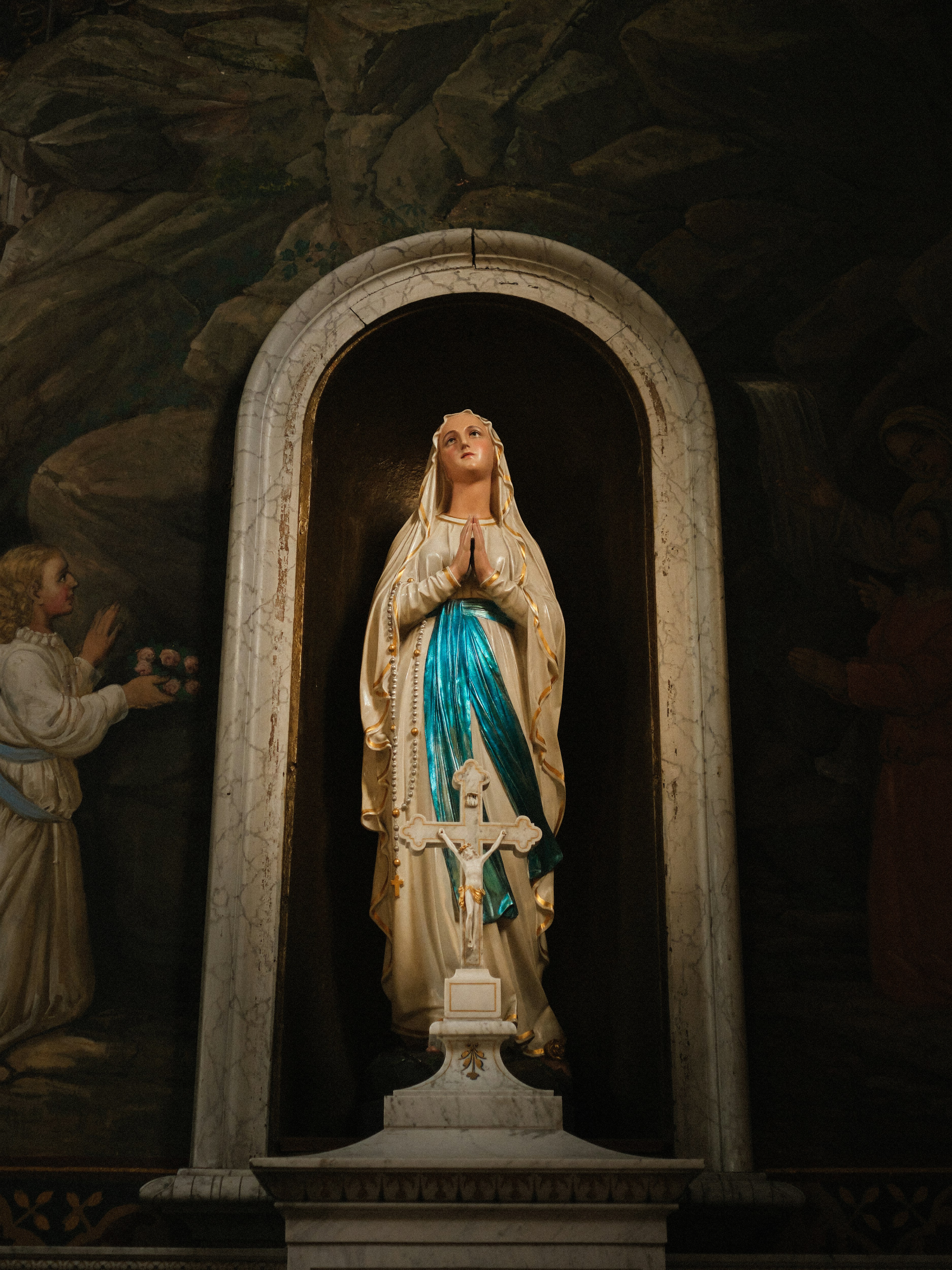 Statue of mary praying in a niche