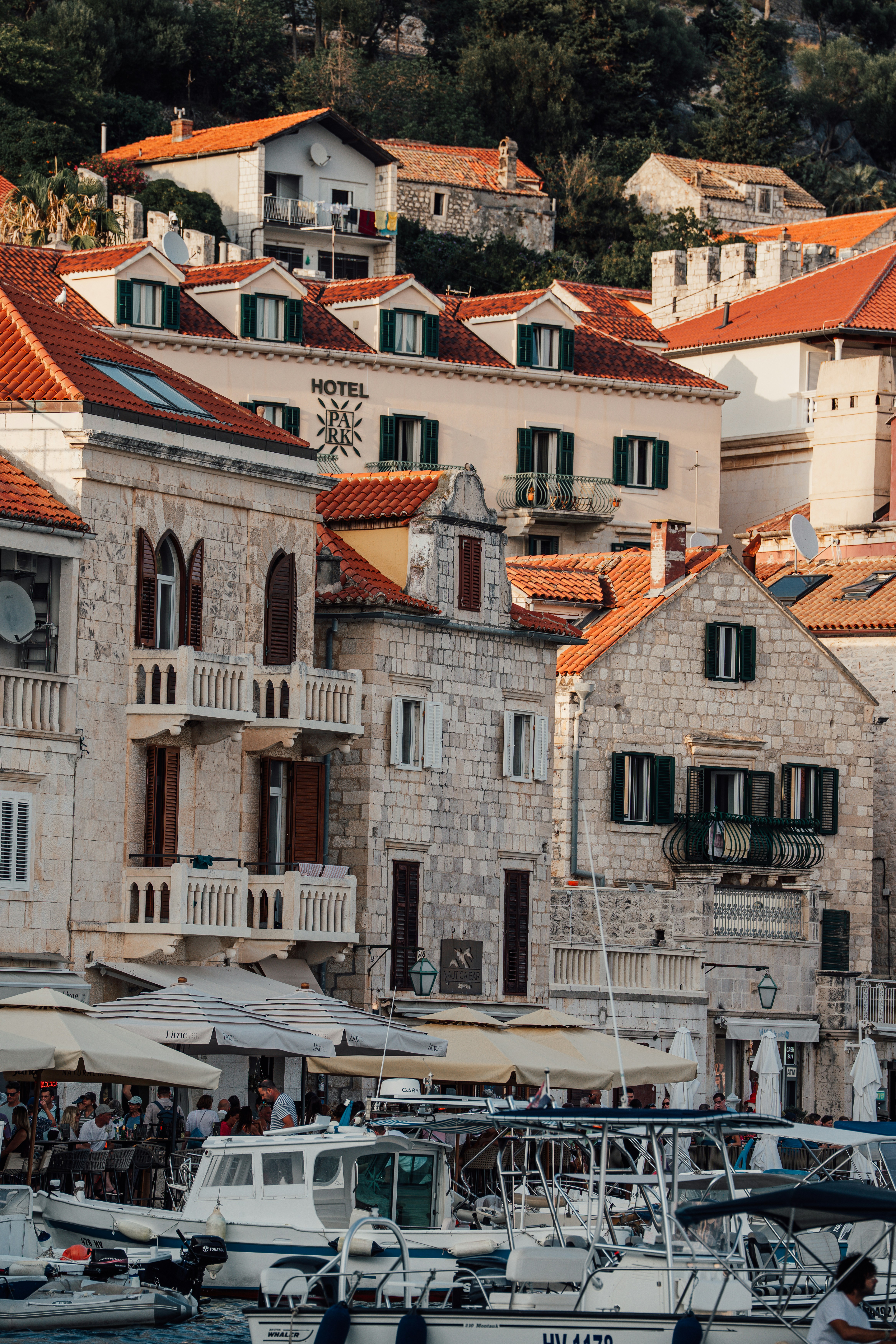 Charming coastal buildings with terracotta roofs overlook a busy harbor filled with boats. The scene captures the vibrant atmosphere of seaside living.