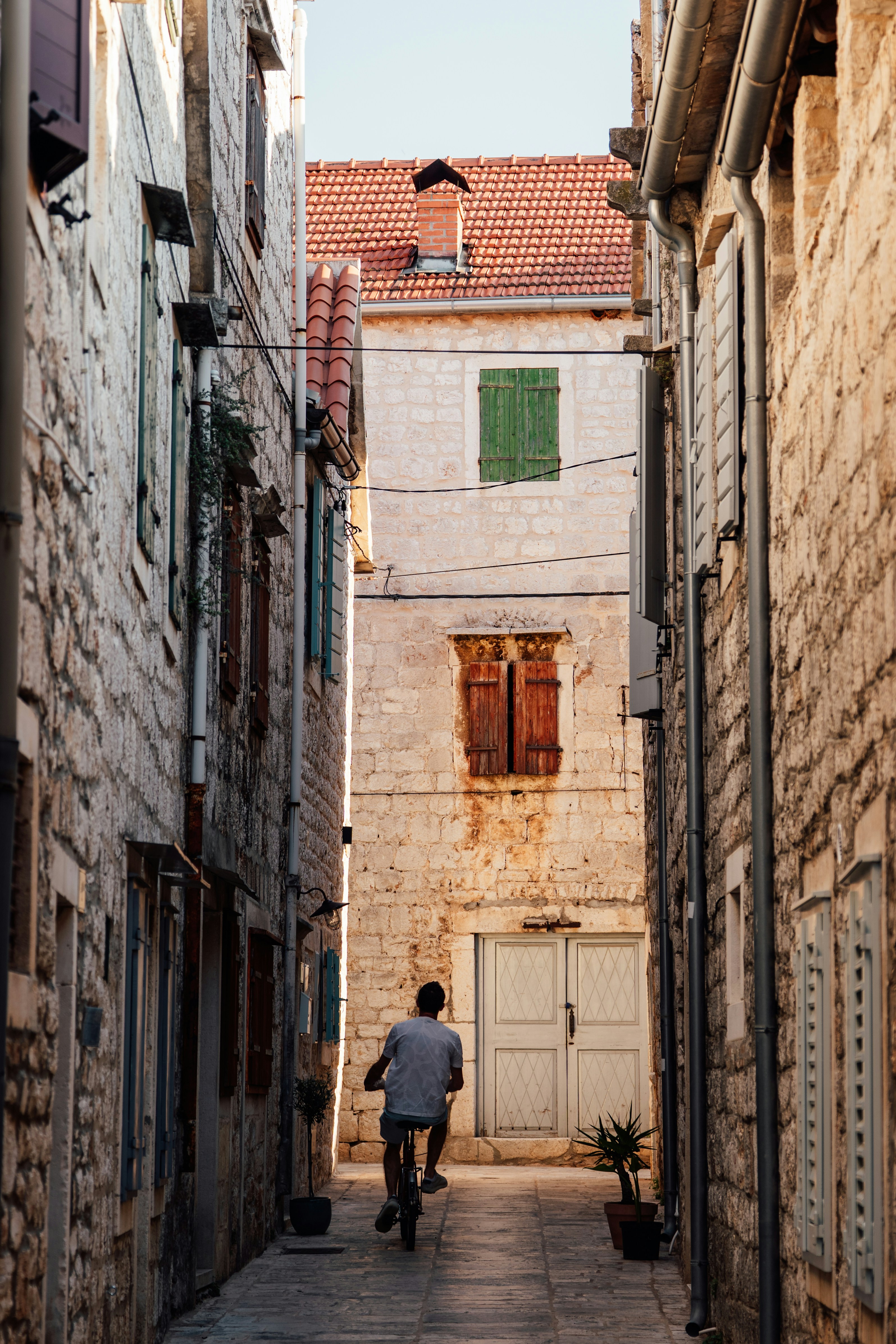 Man rides bicycle down narrow european street.
