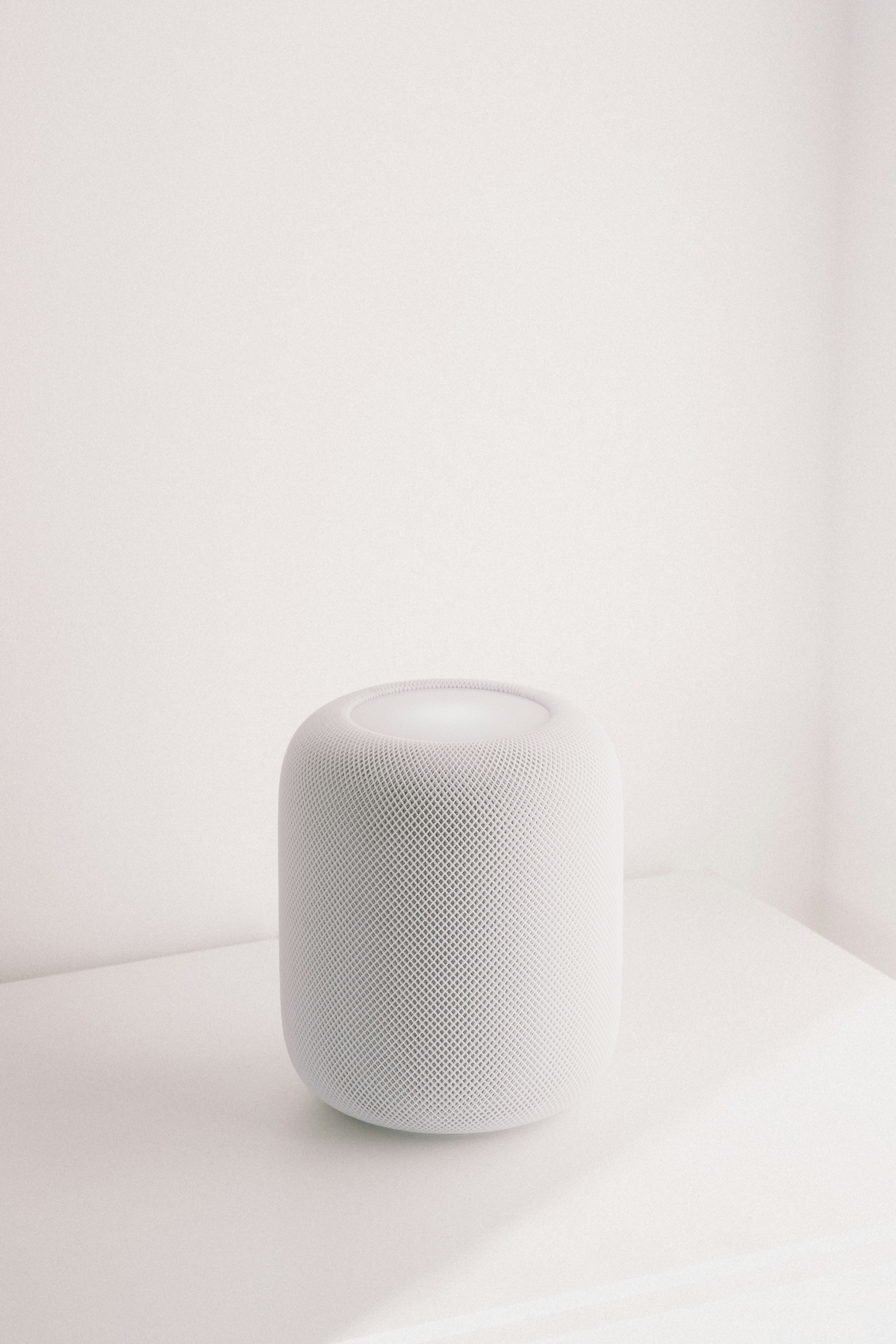 A white smart speaker on a white surface.