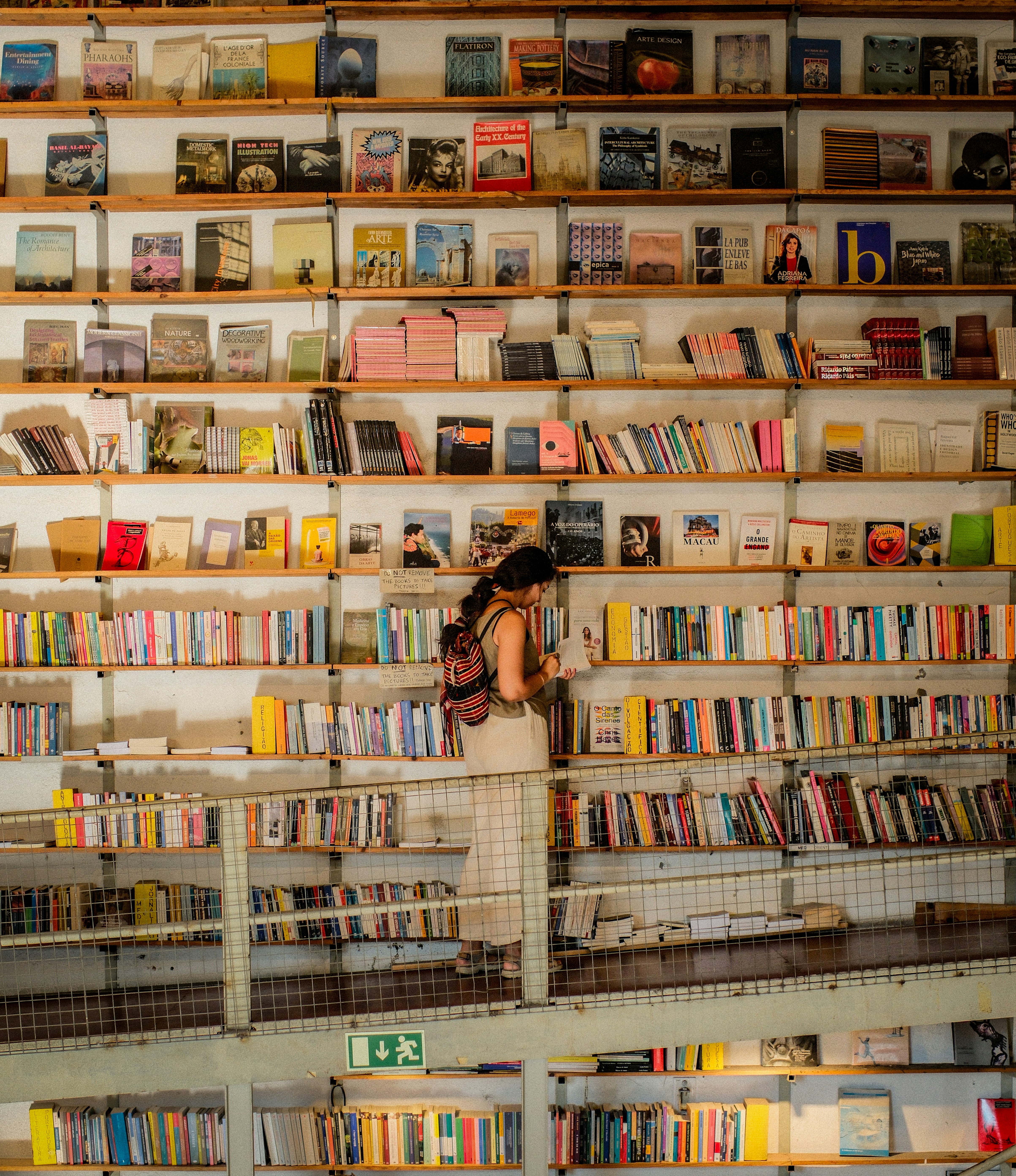 A woman peruses a vibrant bookshelf filled with an array of colorful books in a cozy library setting.