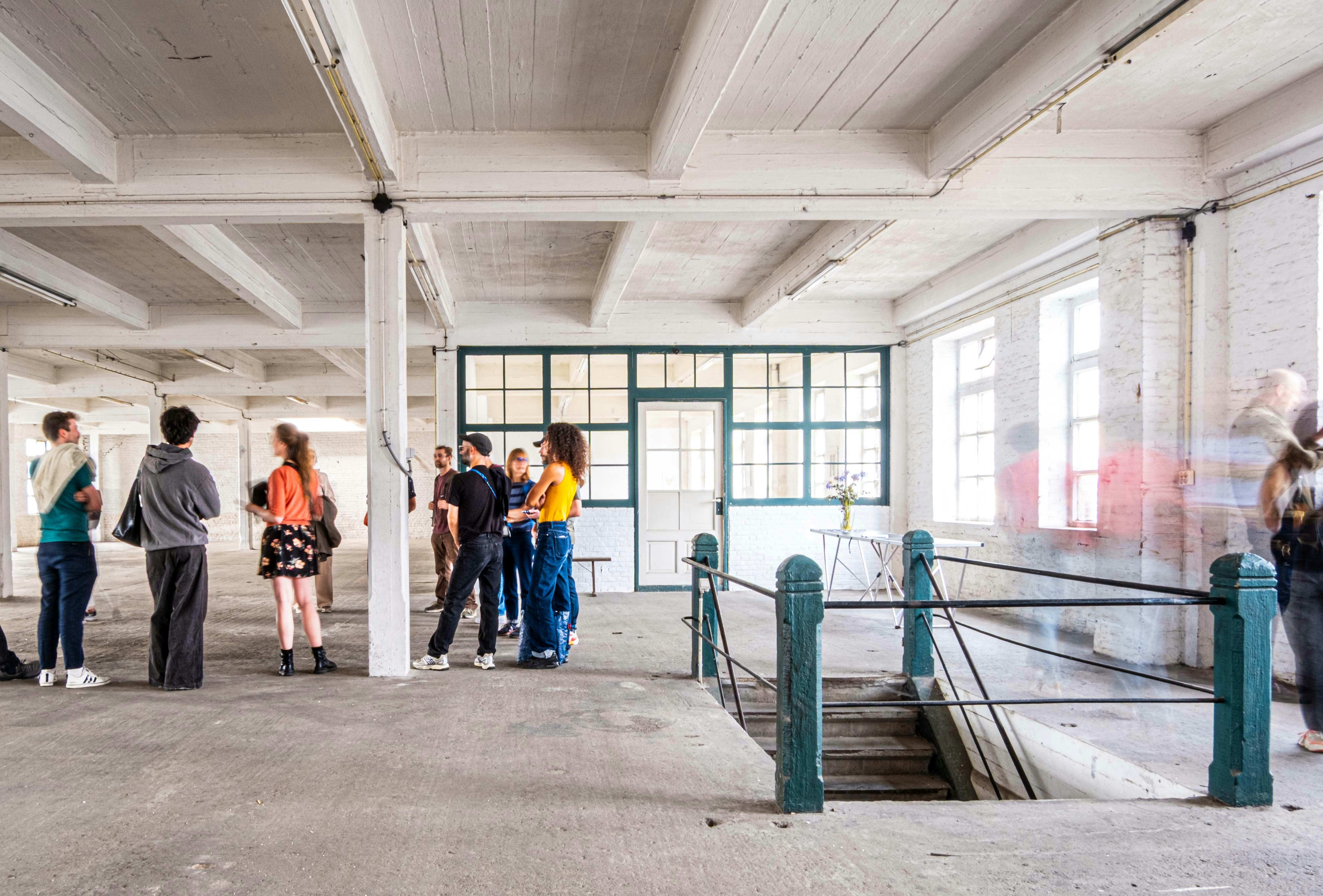 atlas bewery | People gathered in a large, empty industrial space.