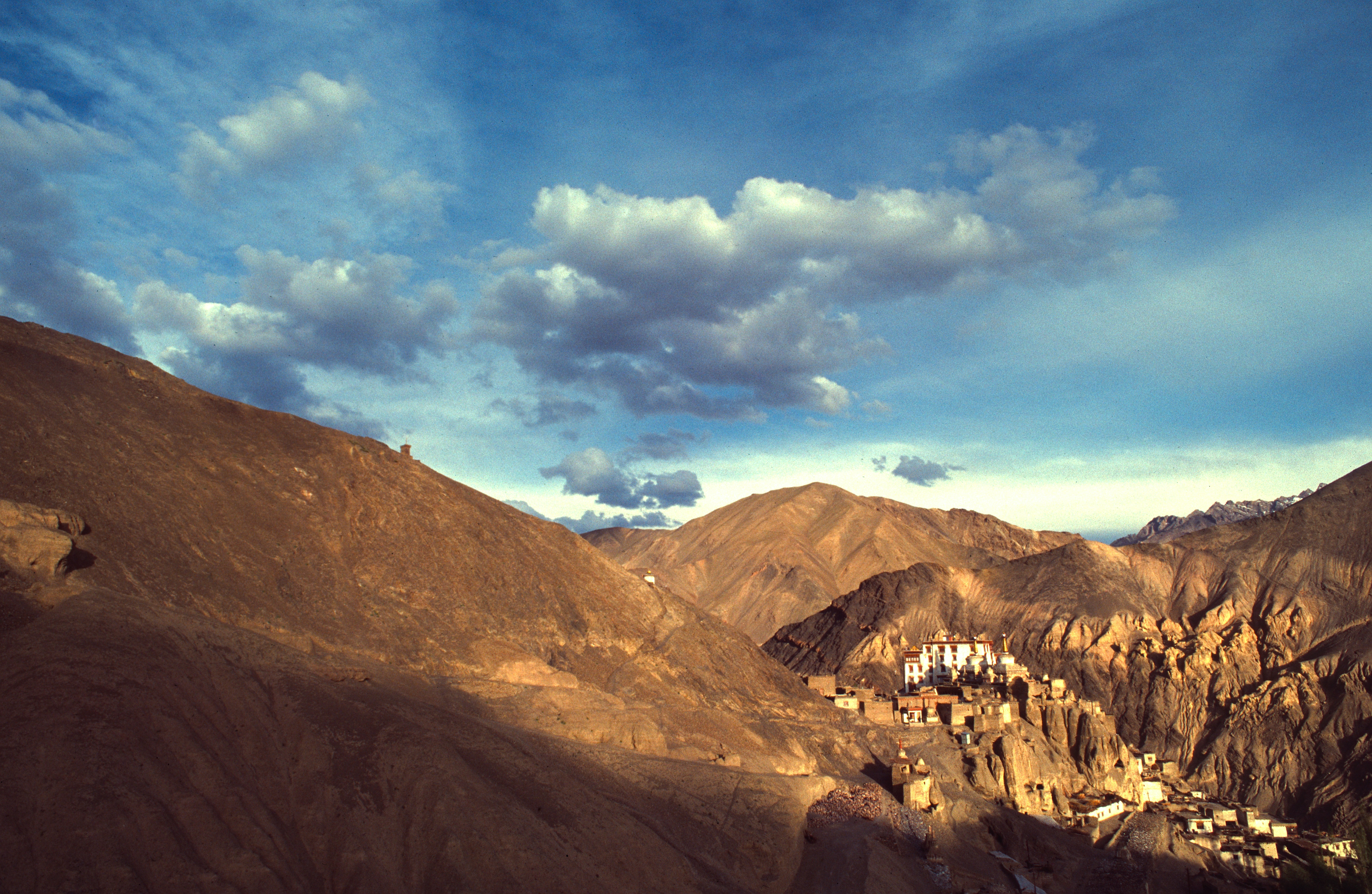 Mountain village nestled in a valley under a cloudy sky