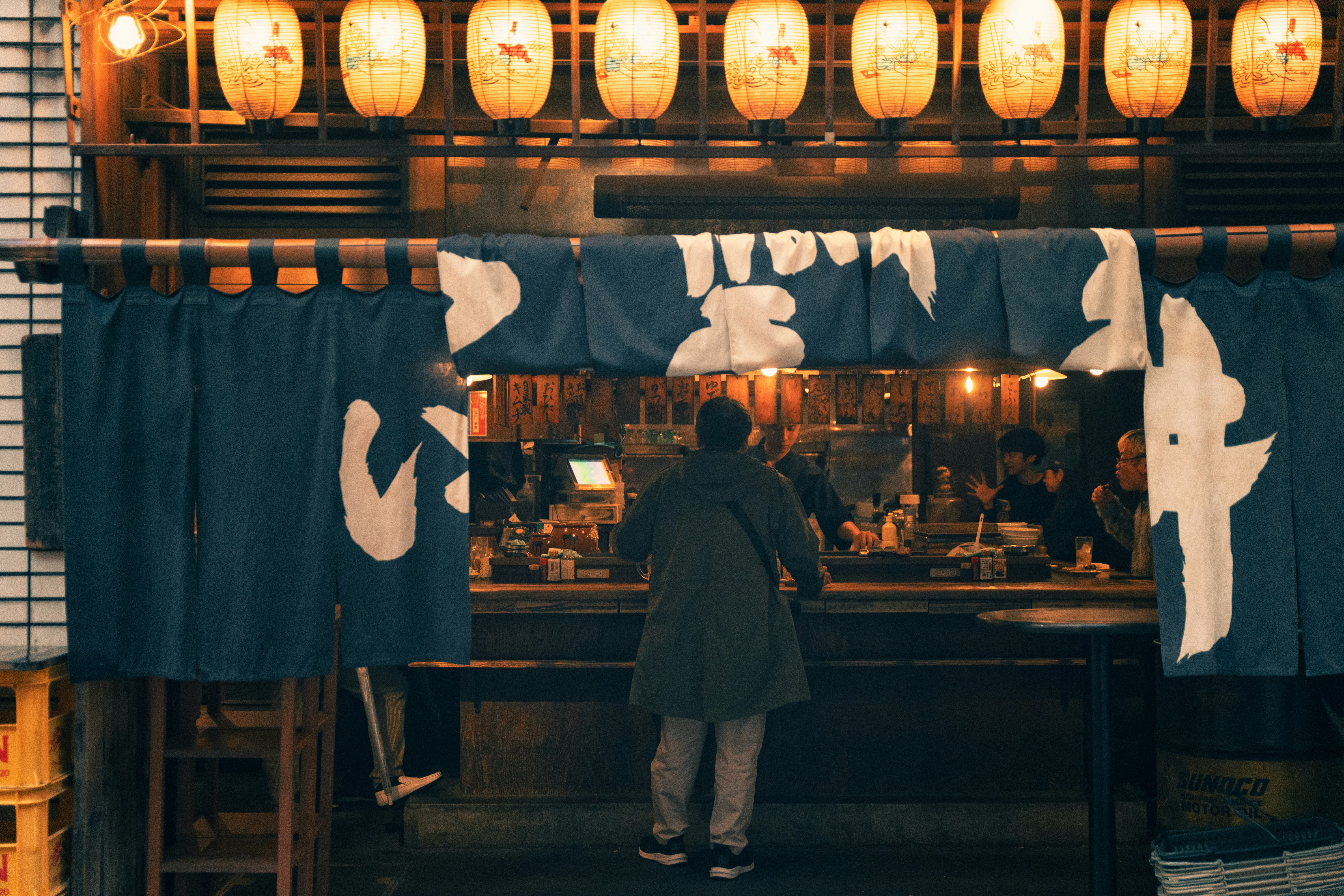 Person entering a dimly lit japanese izakaya restaurant