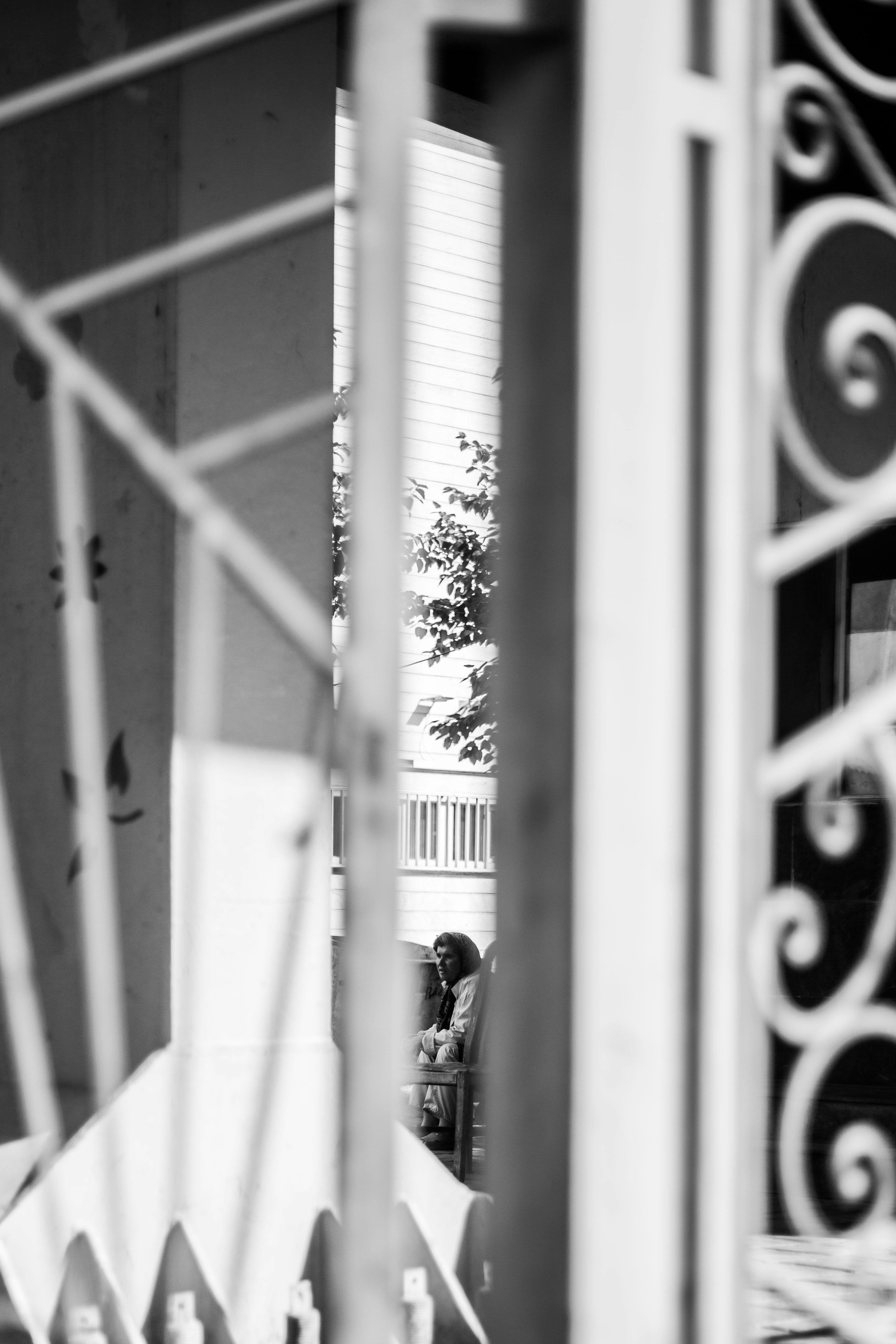 Mental asylum، cuz they live in unknown world. Maybe their reality works better. | Person sitting on a porch behind a gate