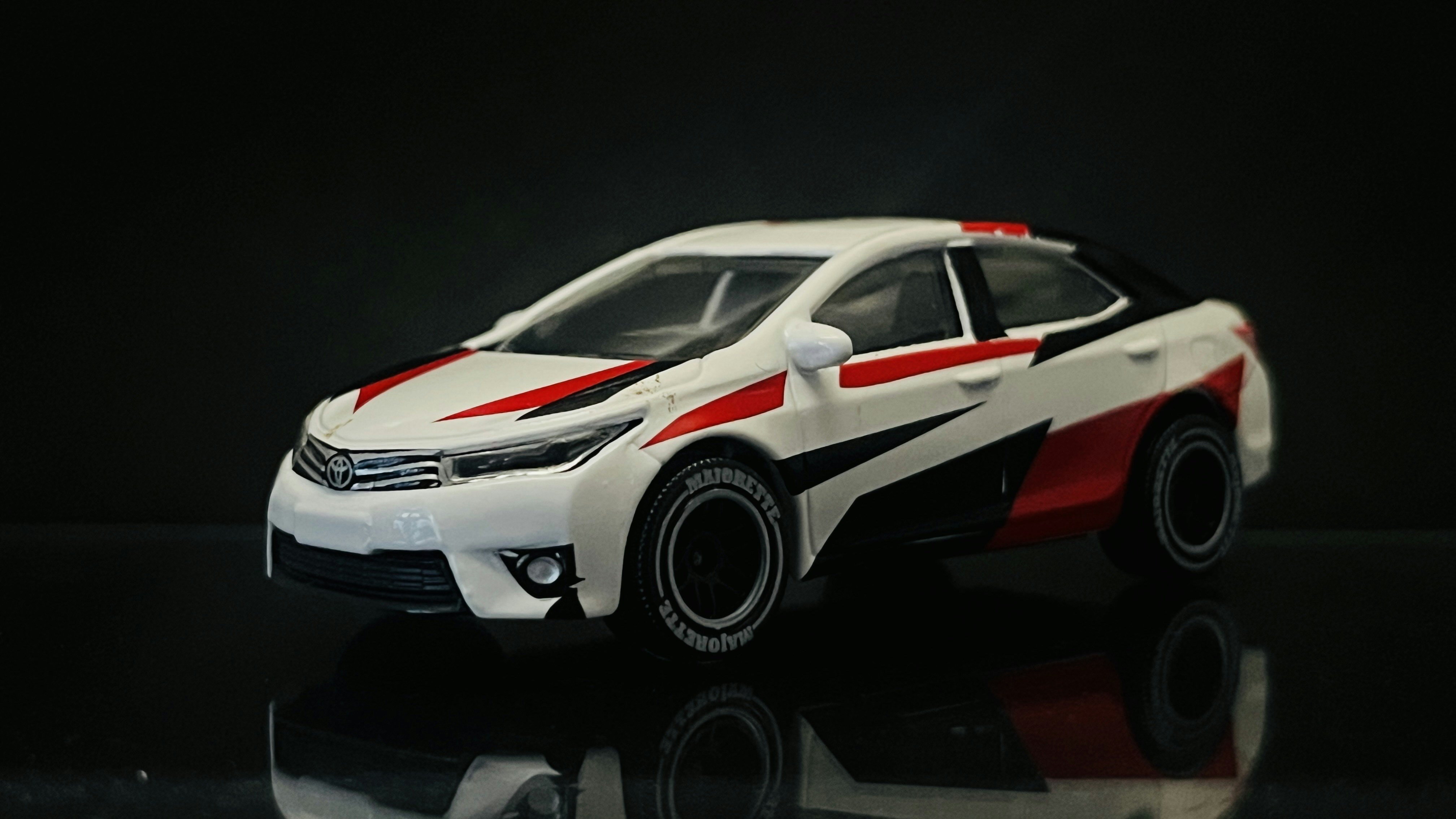 A detailed model car featuring a bold white and red design, showcased against a dark backdrop. The sleek lines and vibrant colors highlight its craftsmanship.