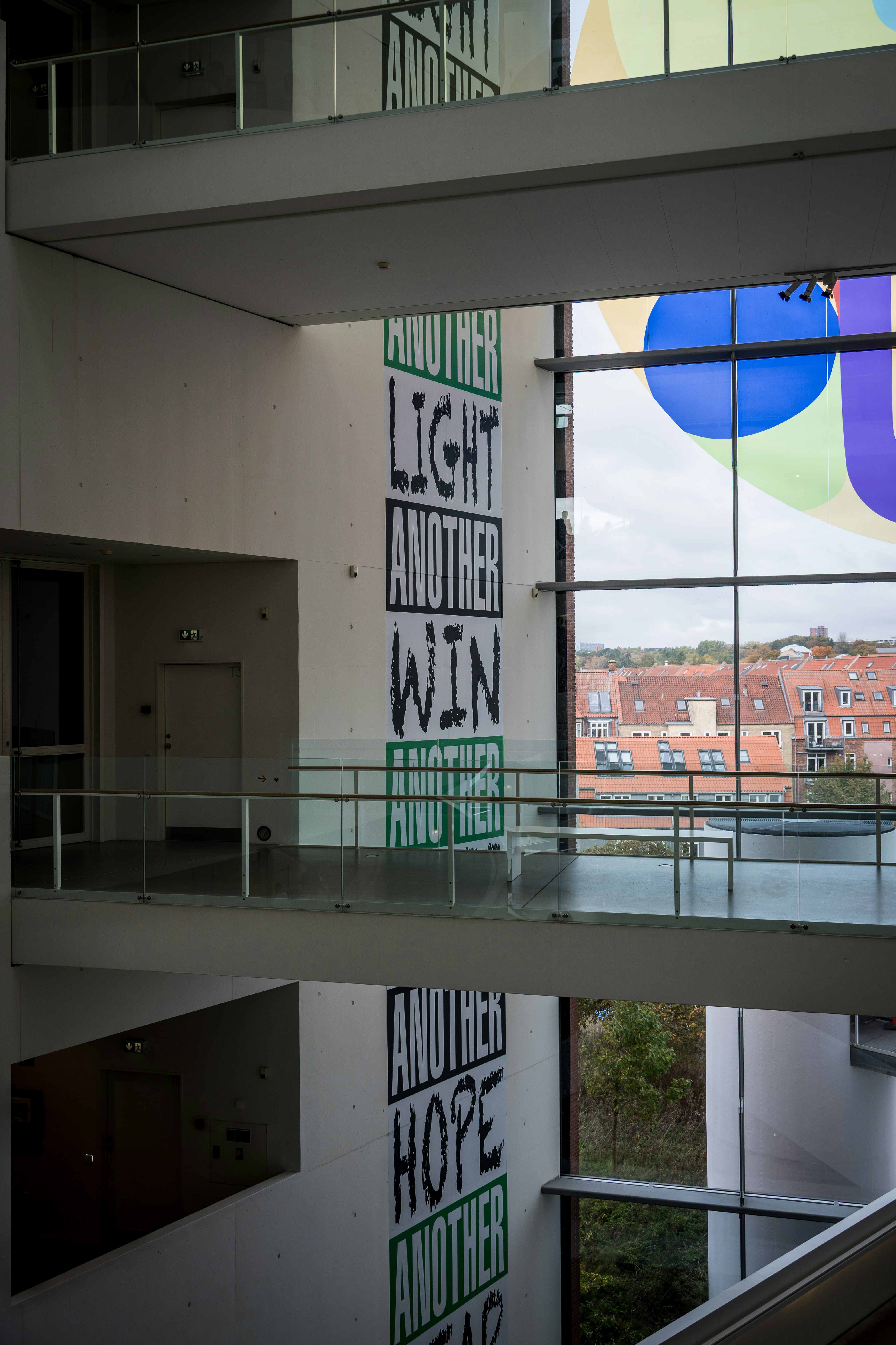 Vertical Echoes in an Atrium: Repeating ANOTHER banners frame a city view