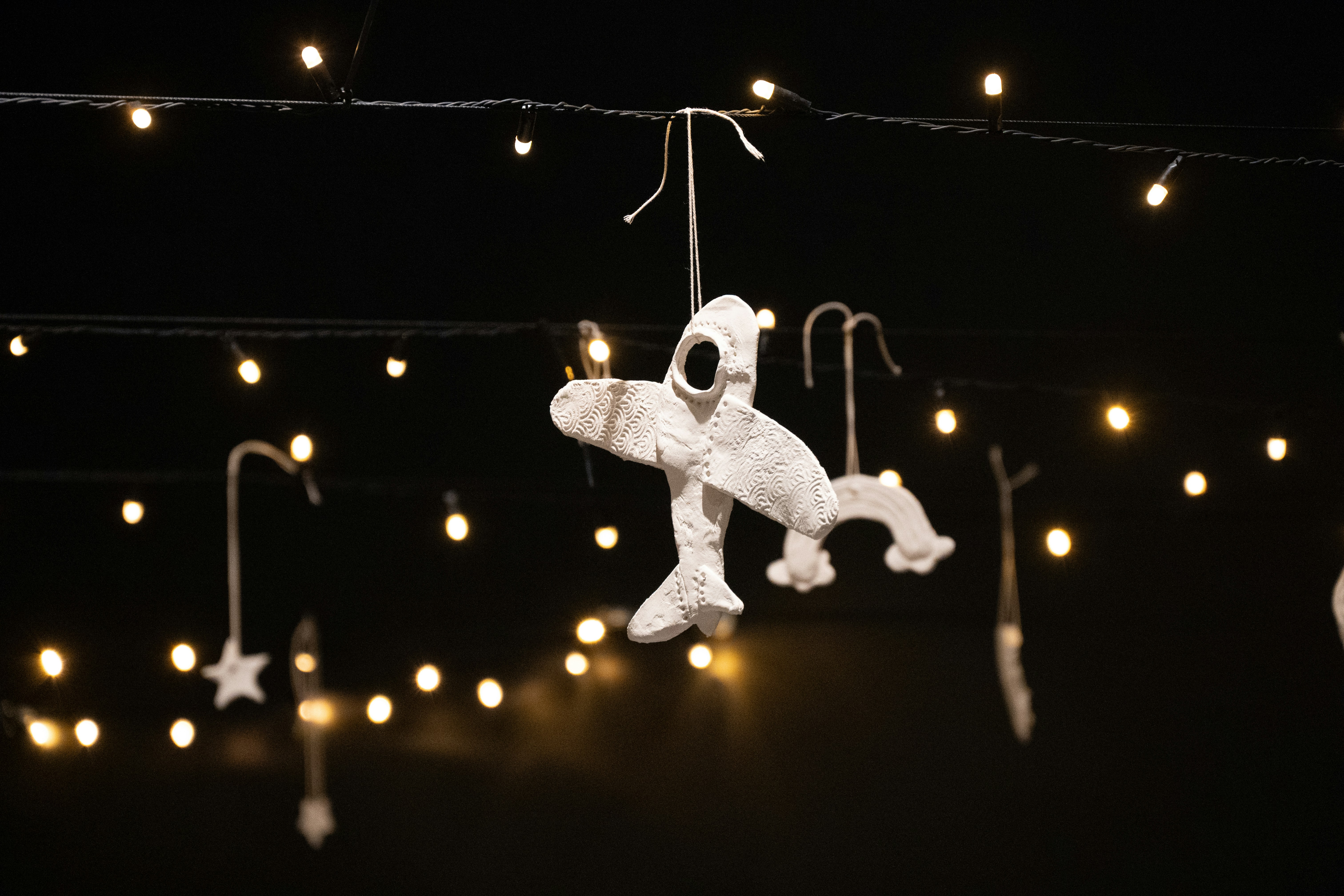White plush dog ornaments hang from string lights