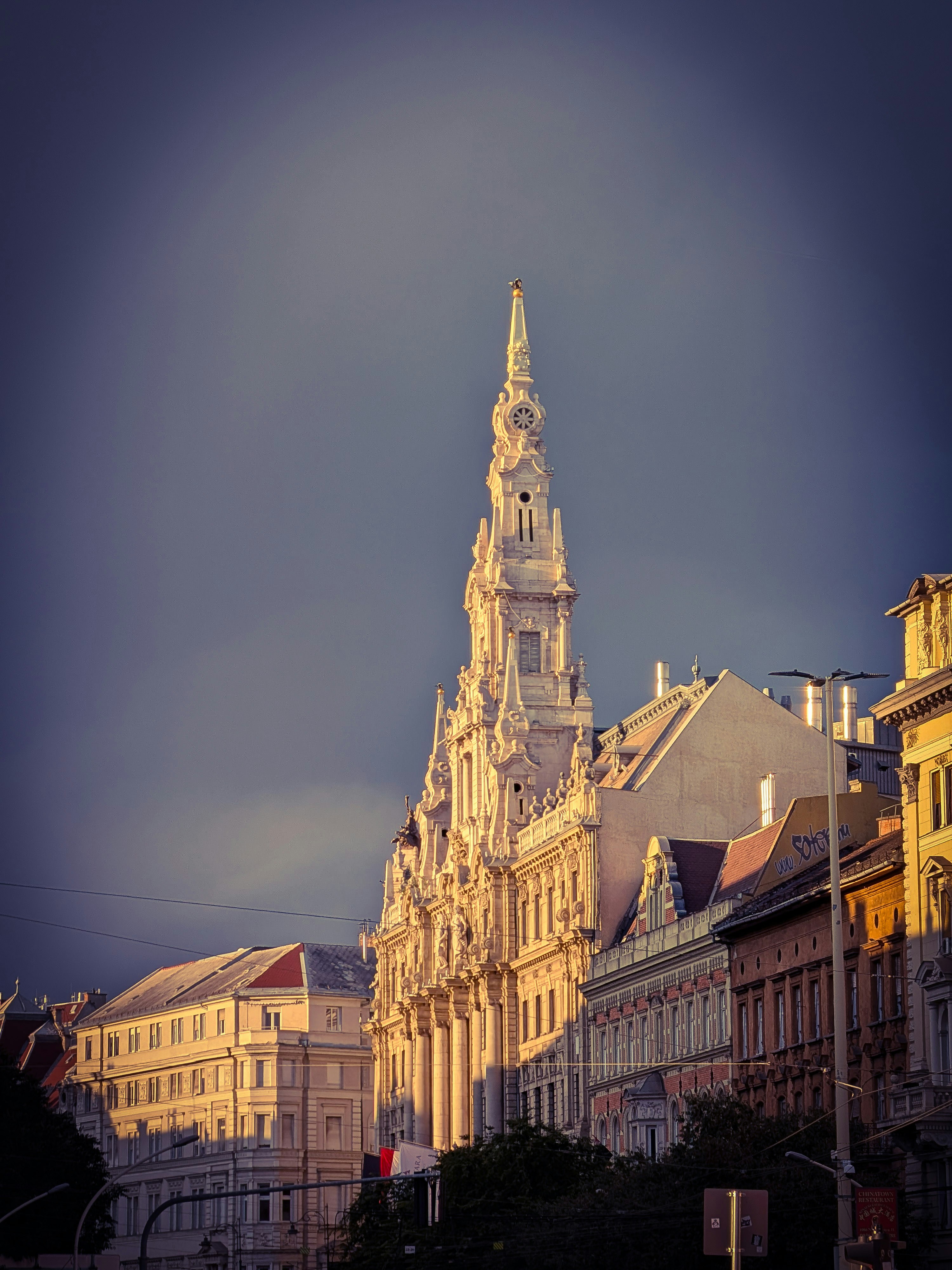 Ornate building with a towering spire under a moody sky, showcasing architectural grandeur and intricate details.