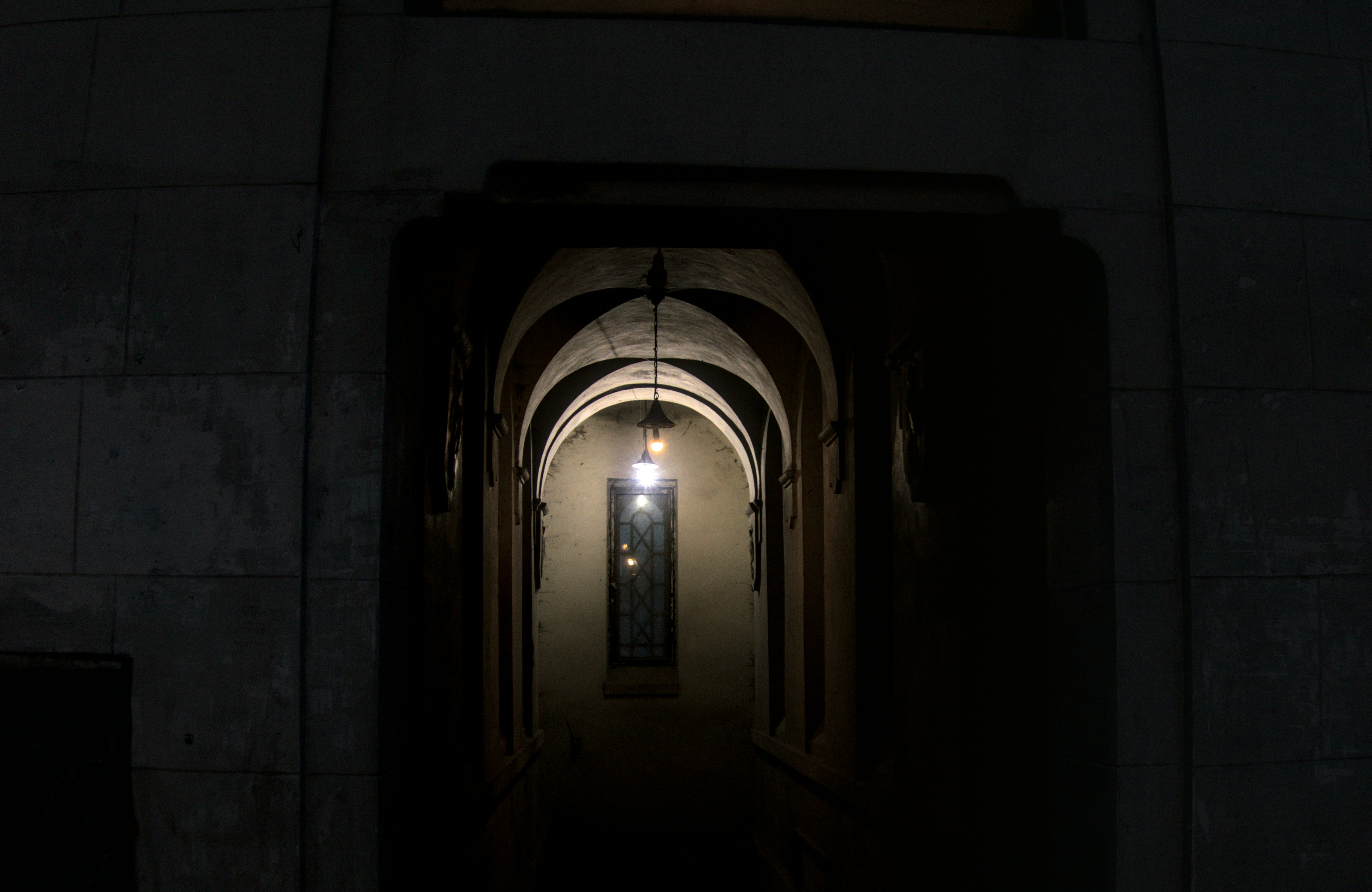 Dark arched hallway with a light at the end
