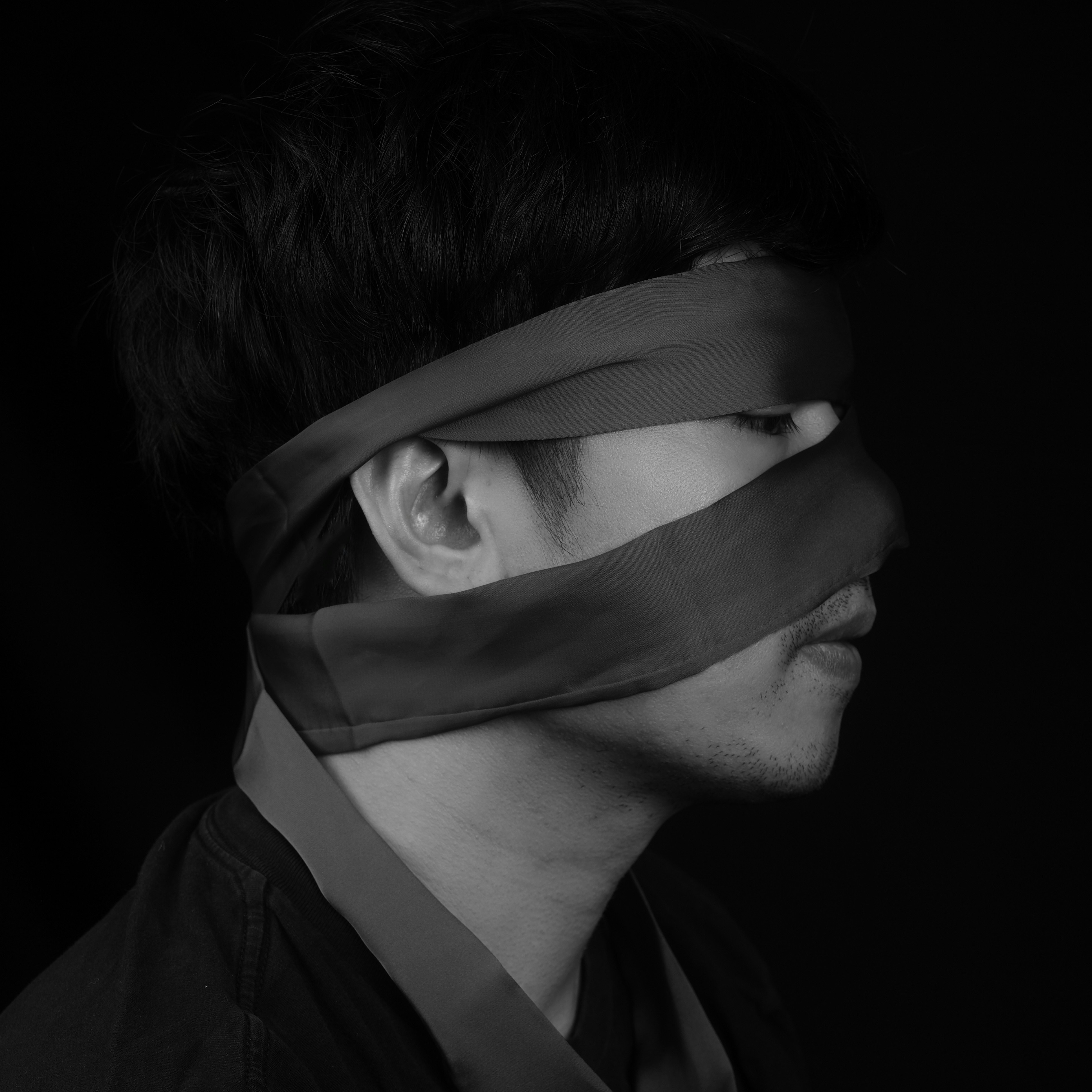 A monochromatic portrait of a man with a blindfold, symbolizing introspection and the exploration of inner thoughts.