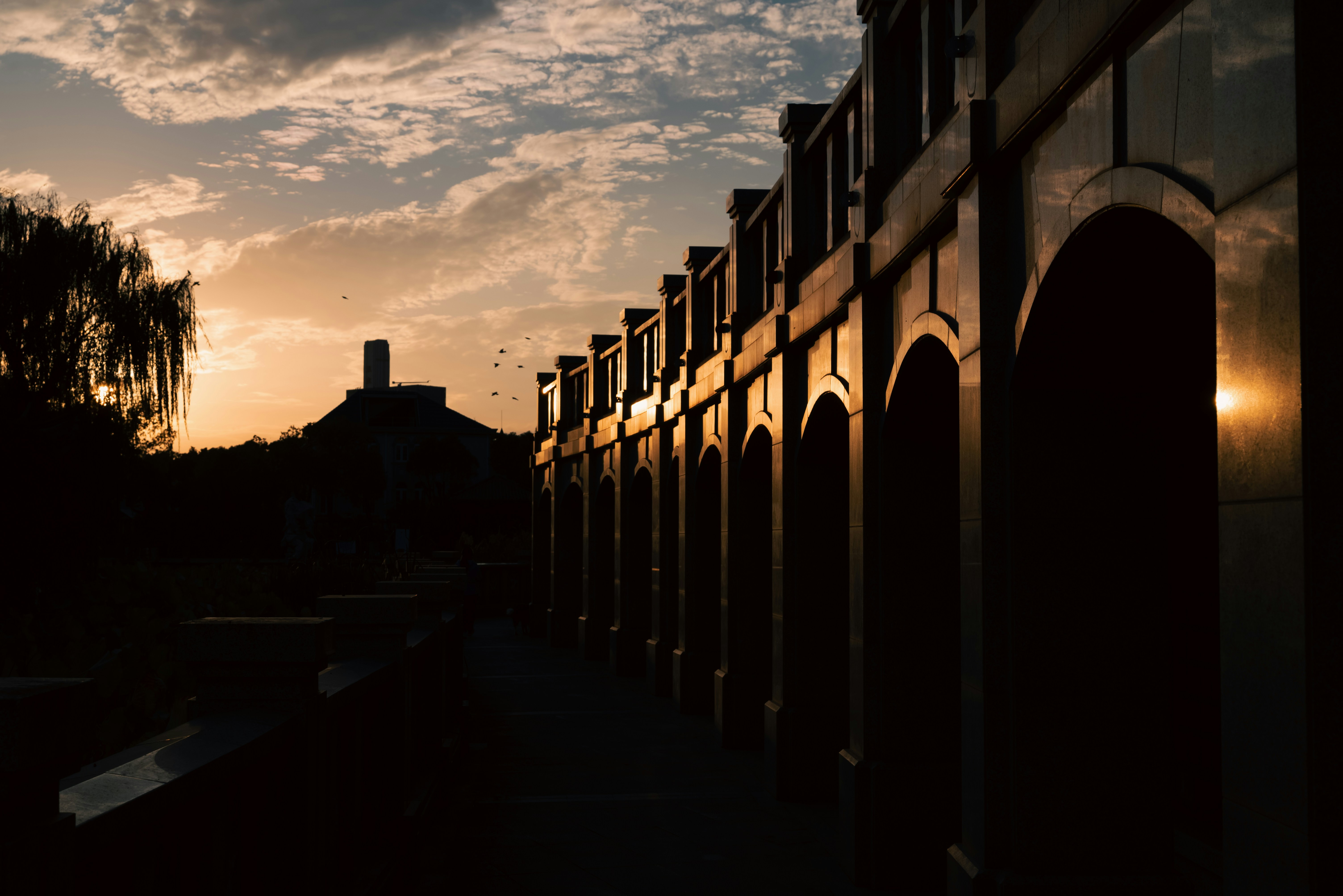 Arched structures cast long shadows against a vibrant sunset, creating a dramatic interplay of light and dark.