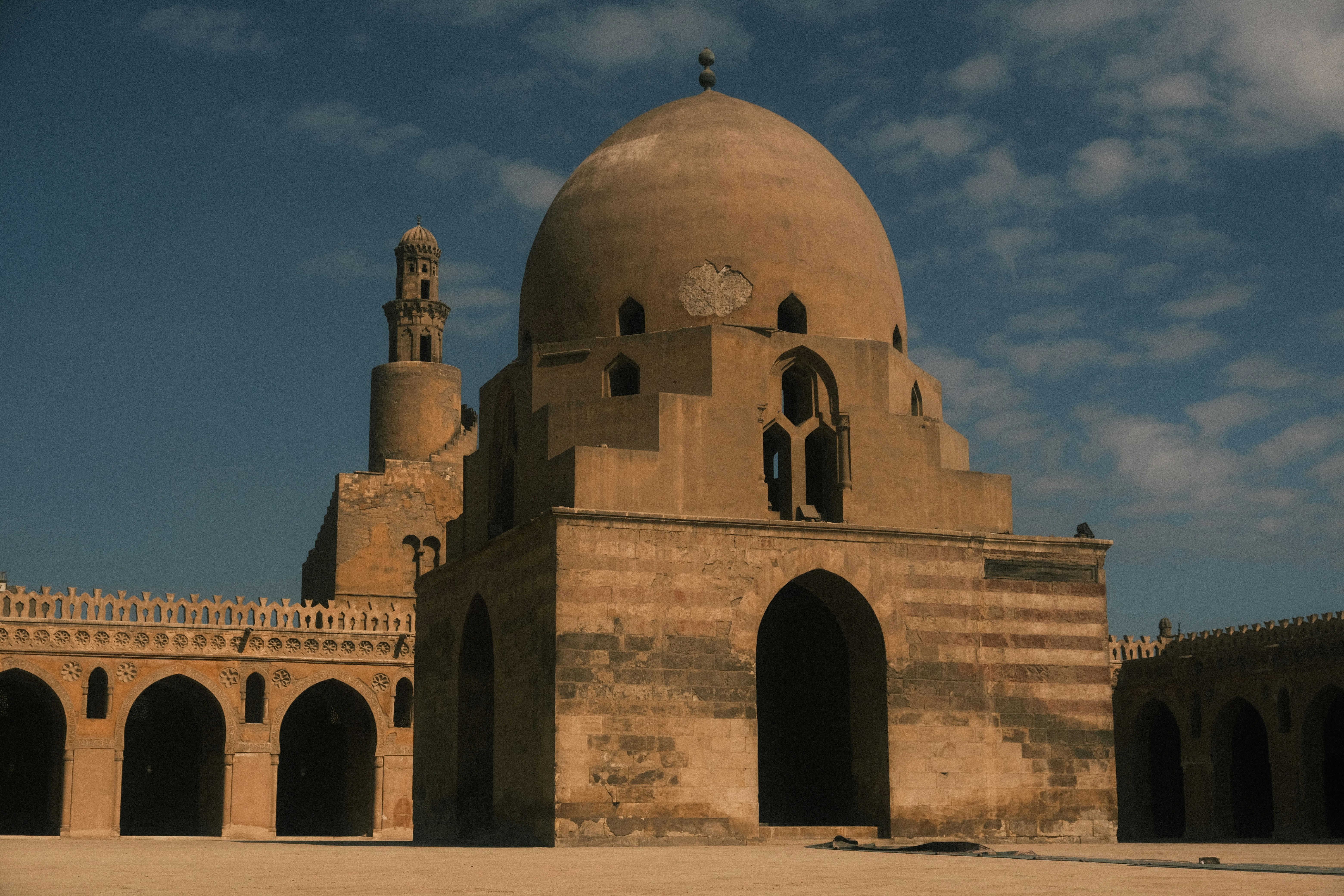 ibn tulun mosque, cairo | Ancient mosque with large dome and minaret under blue sky