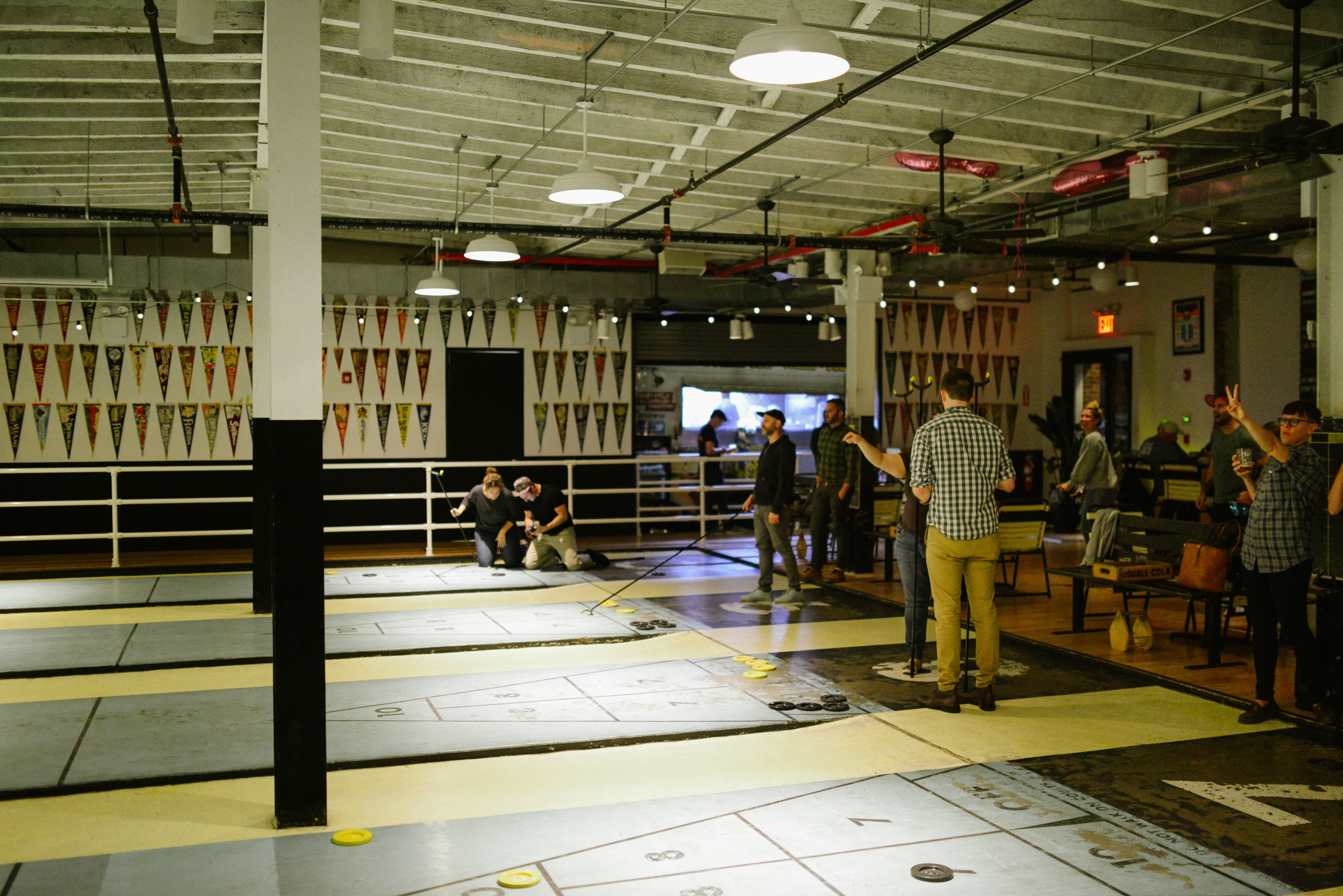 People playing shuffleboard in a large indoor court.