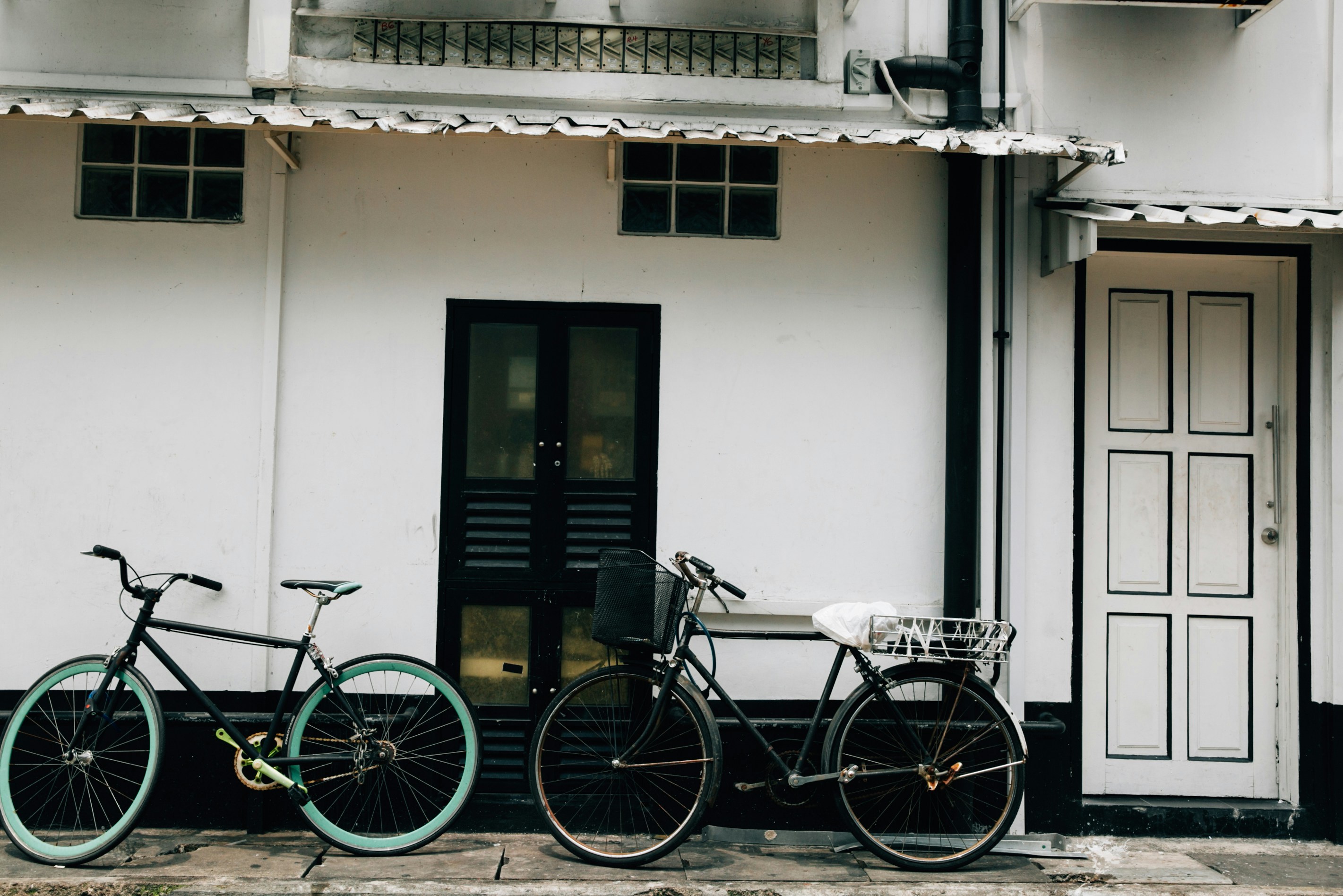 Two bicycles parked against a white wall.
